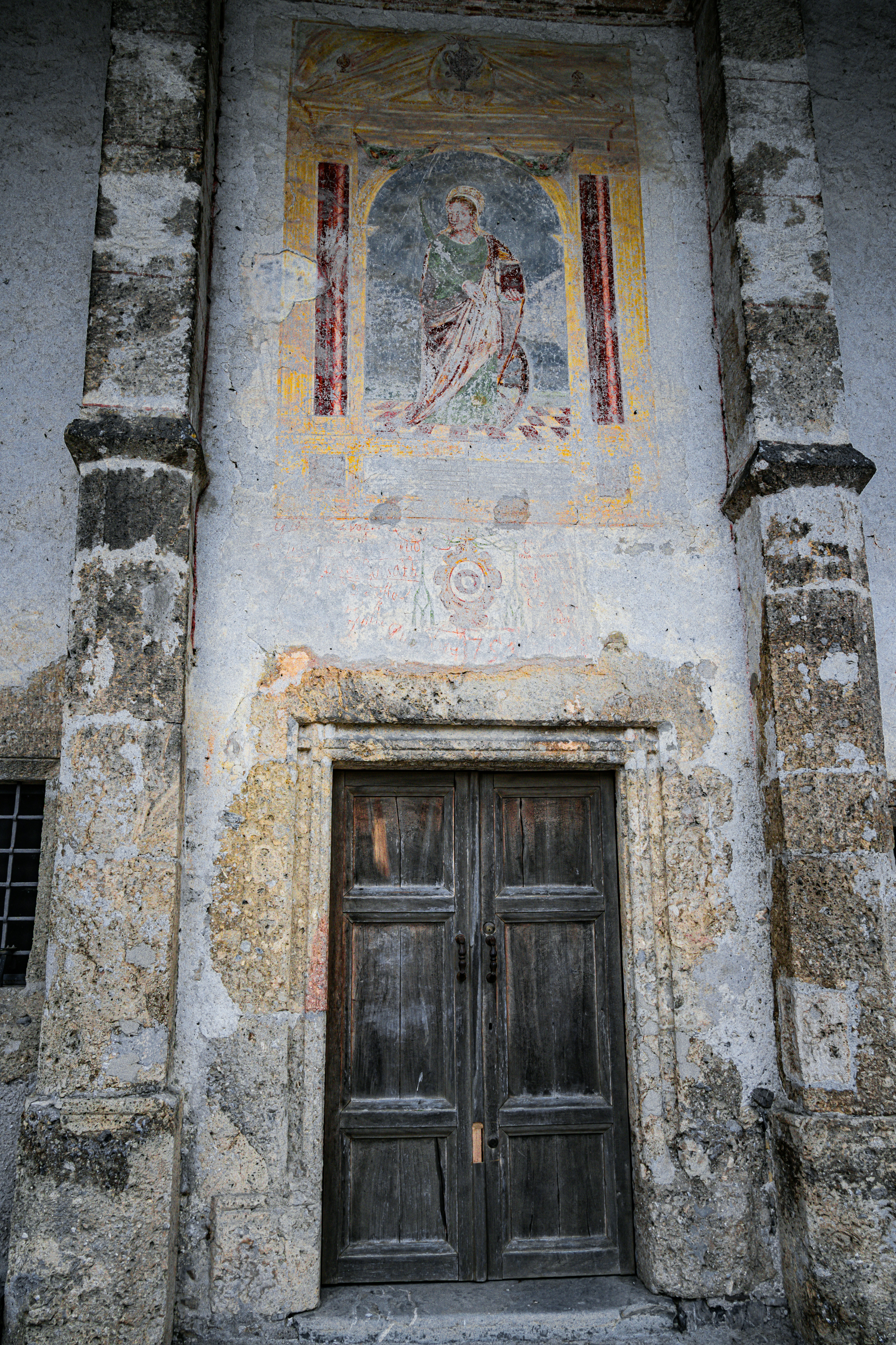 Weathered Fresco Above a Sturdy Door
