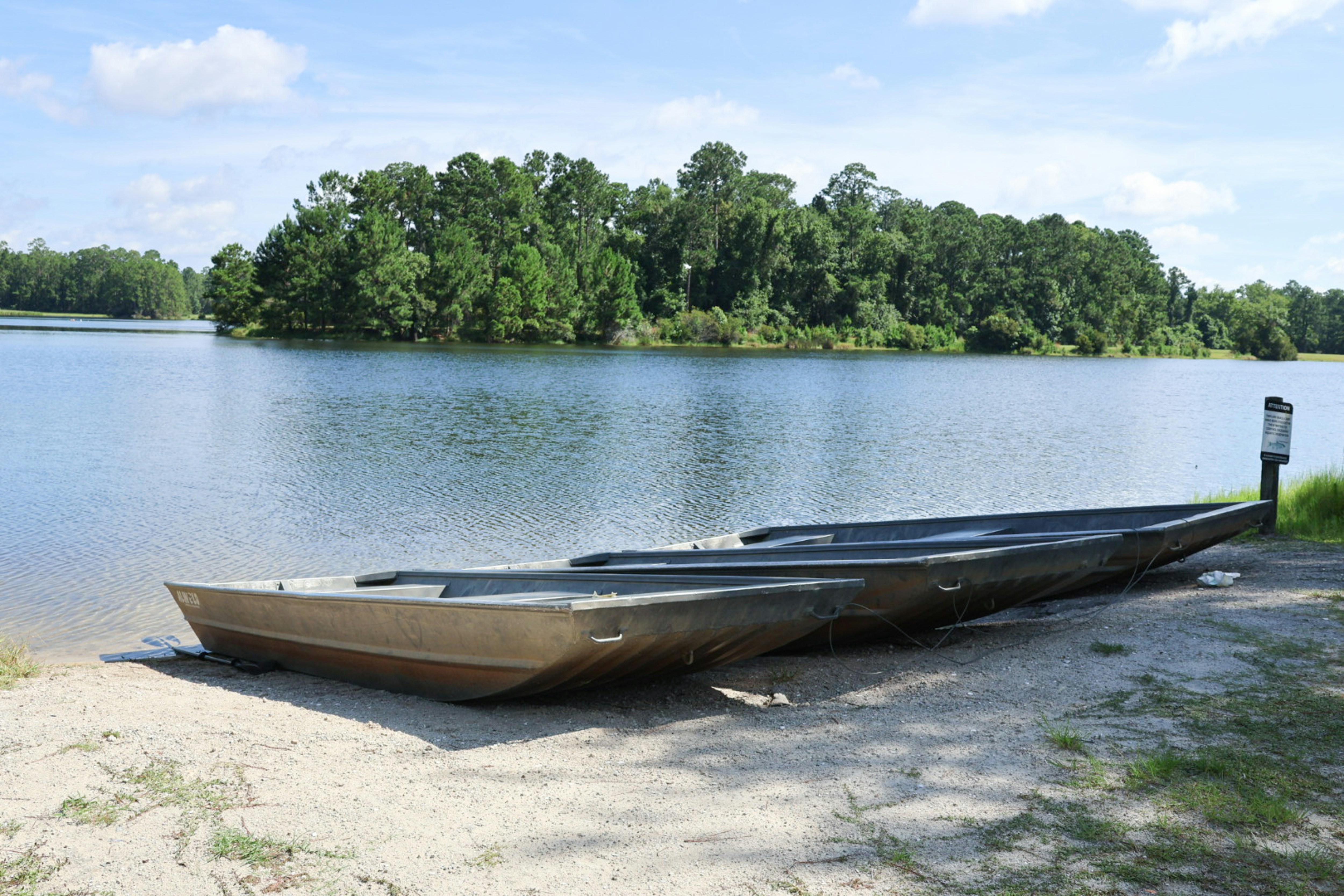 Three Canoes Rest on Shallow Shore Against a Quiet Lake