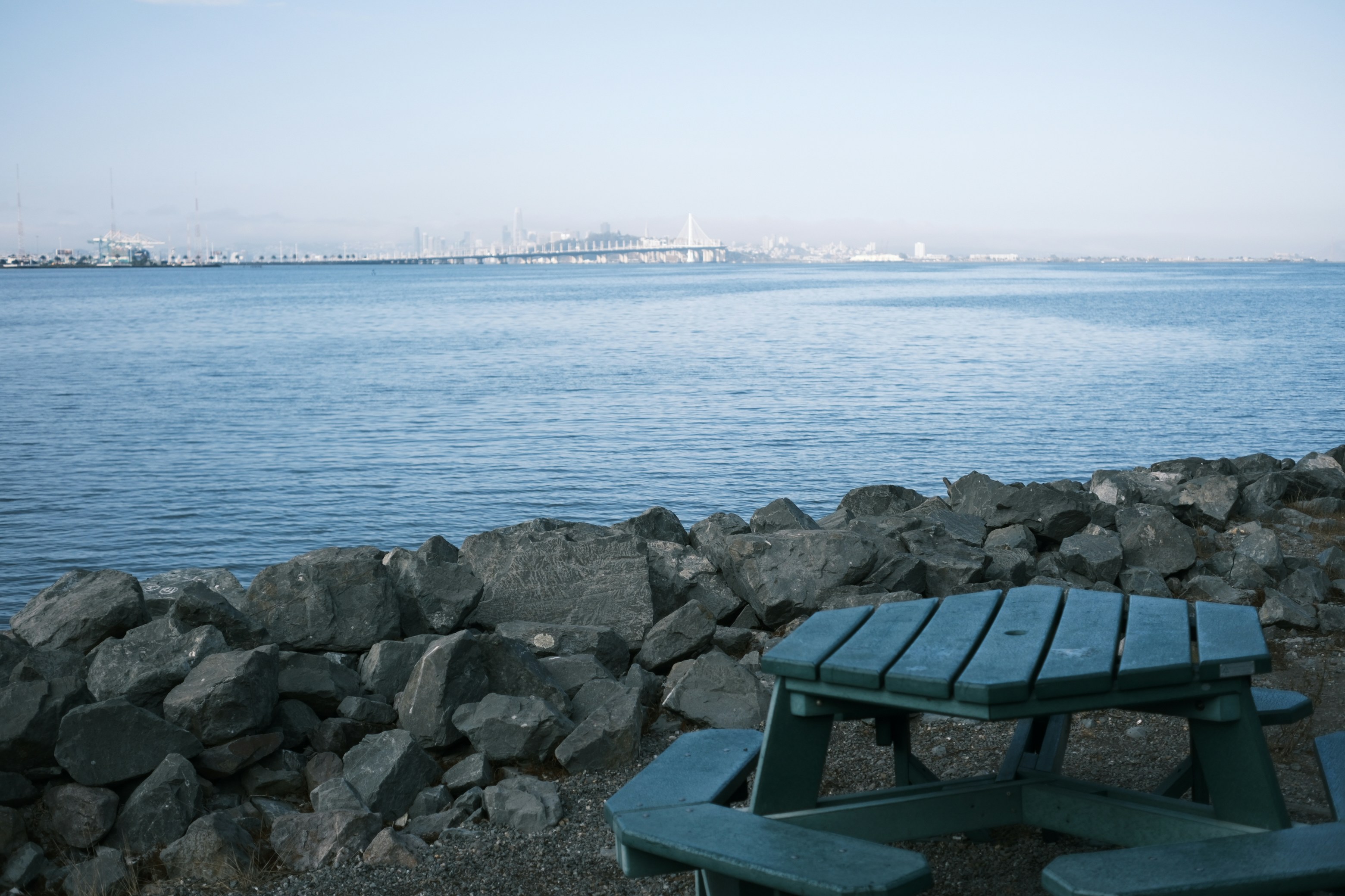 Quiet Shoreline with Weathered Rocks and a Teal Picnic Table