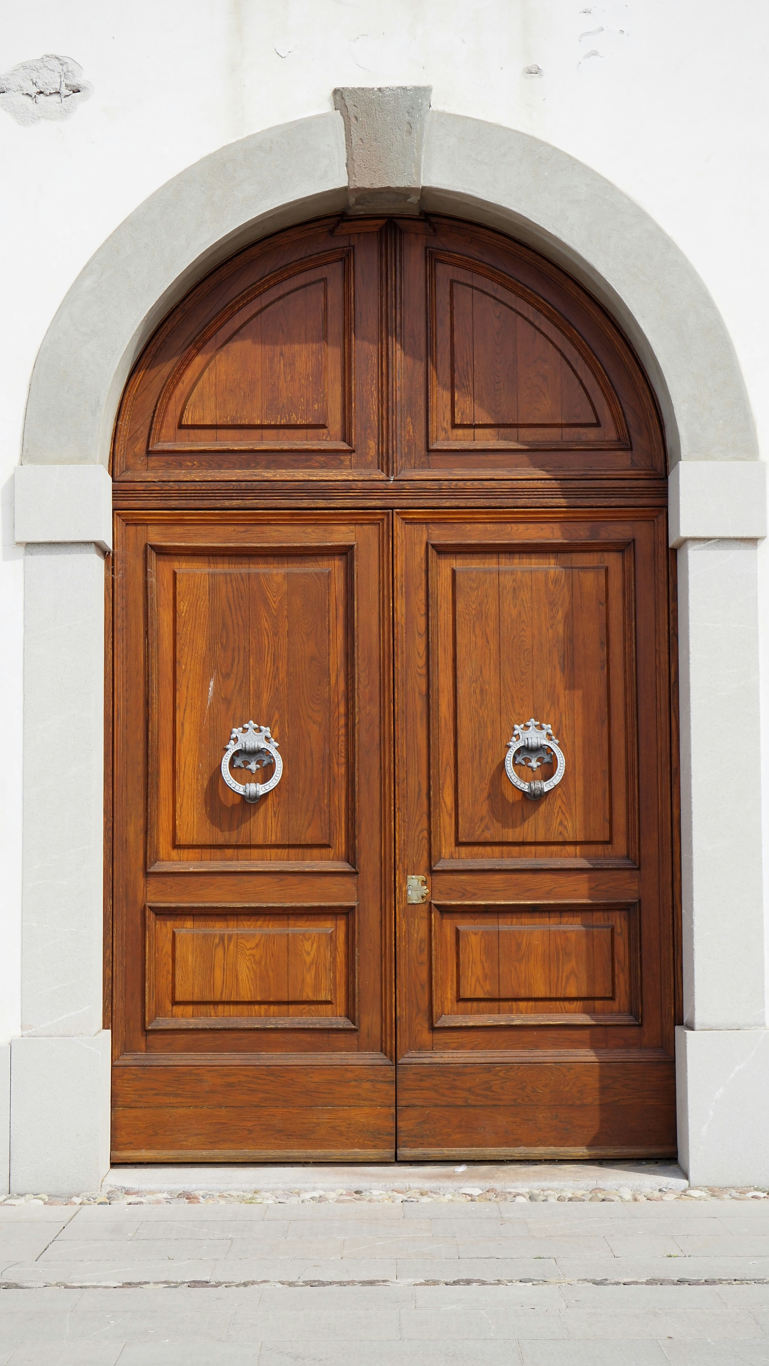 Heritage Door: Carved Panels and Brass Ring Knocker Under Stone Arch