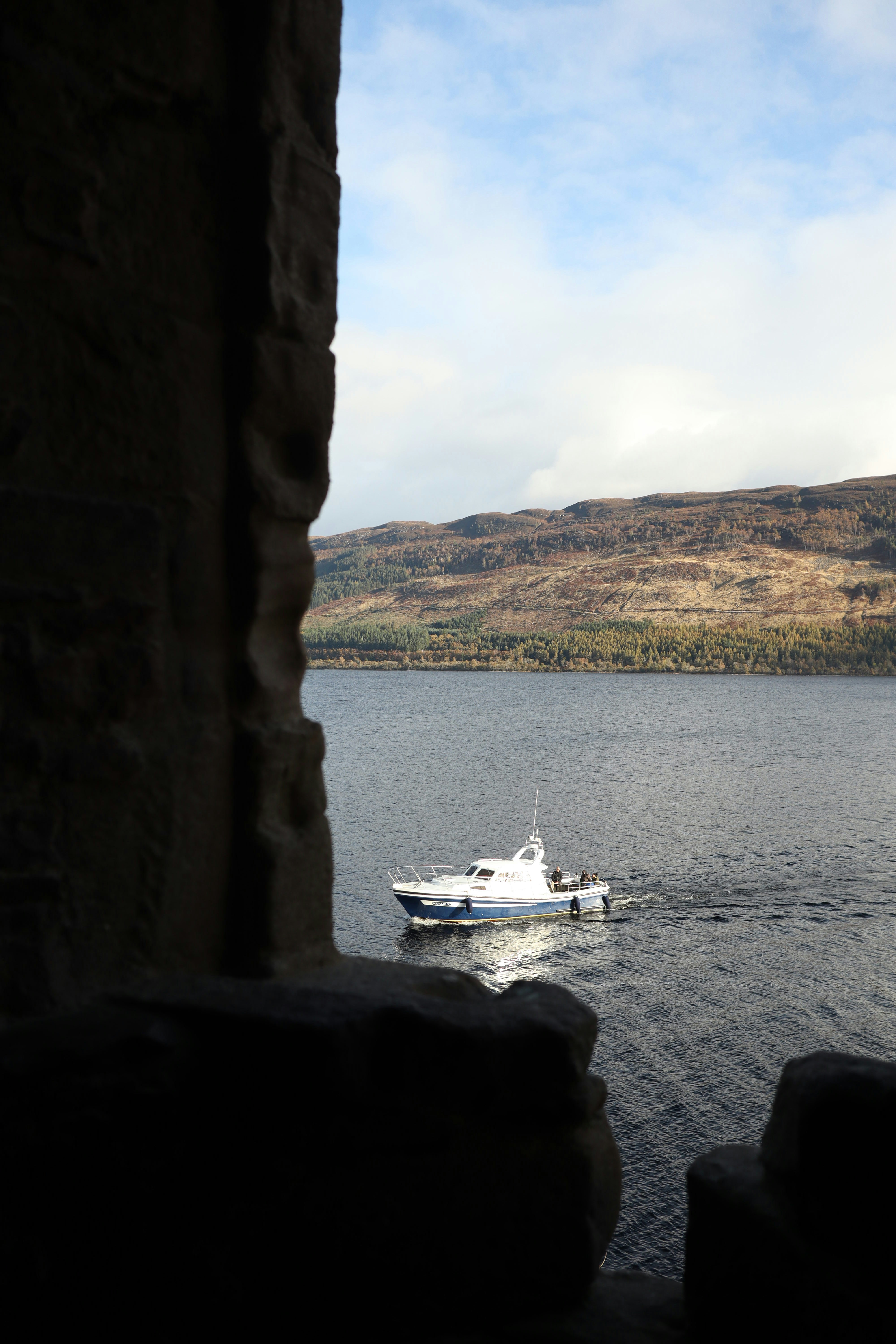 Boat Crossing Between Shadowed Archways into a Quiet Fjord