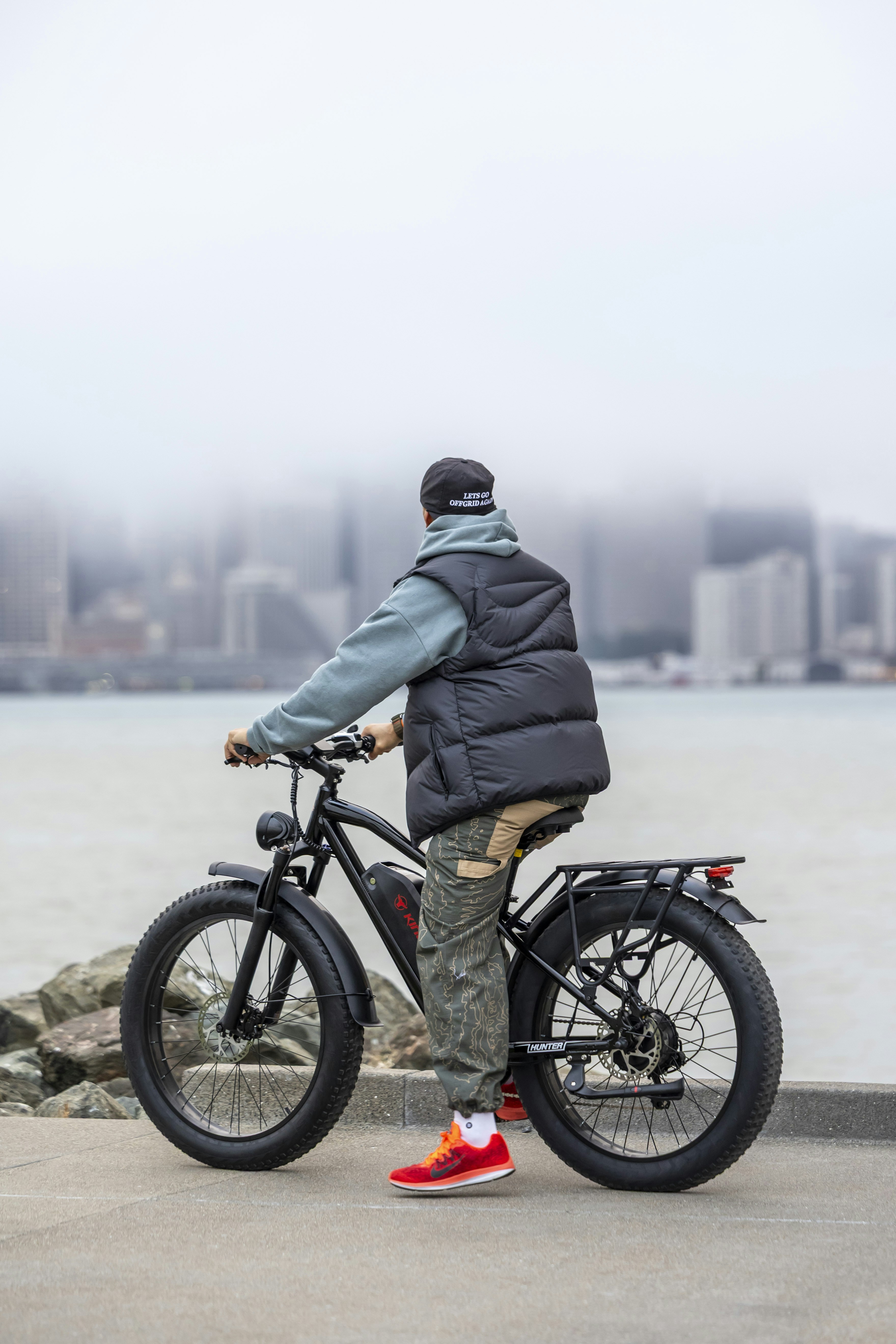 Rider on the Waterfront: puffered silhouette and electric bike at dusk