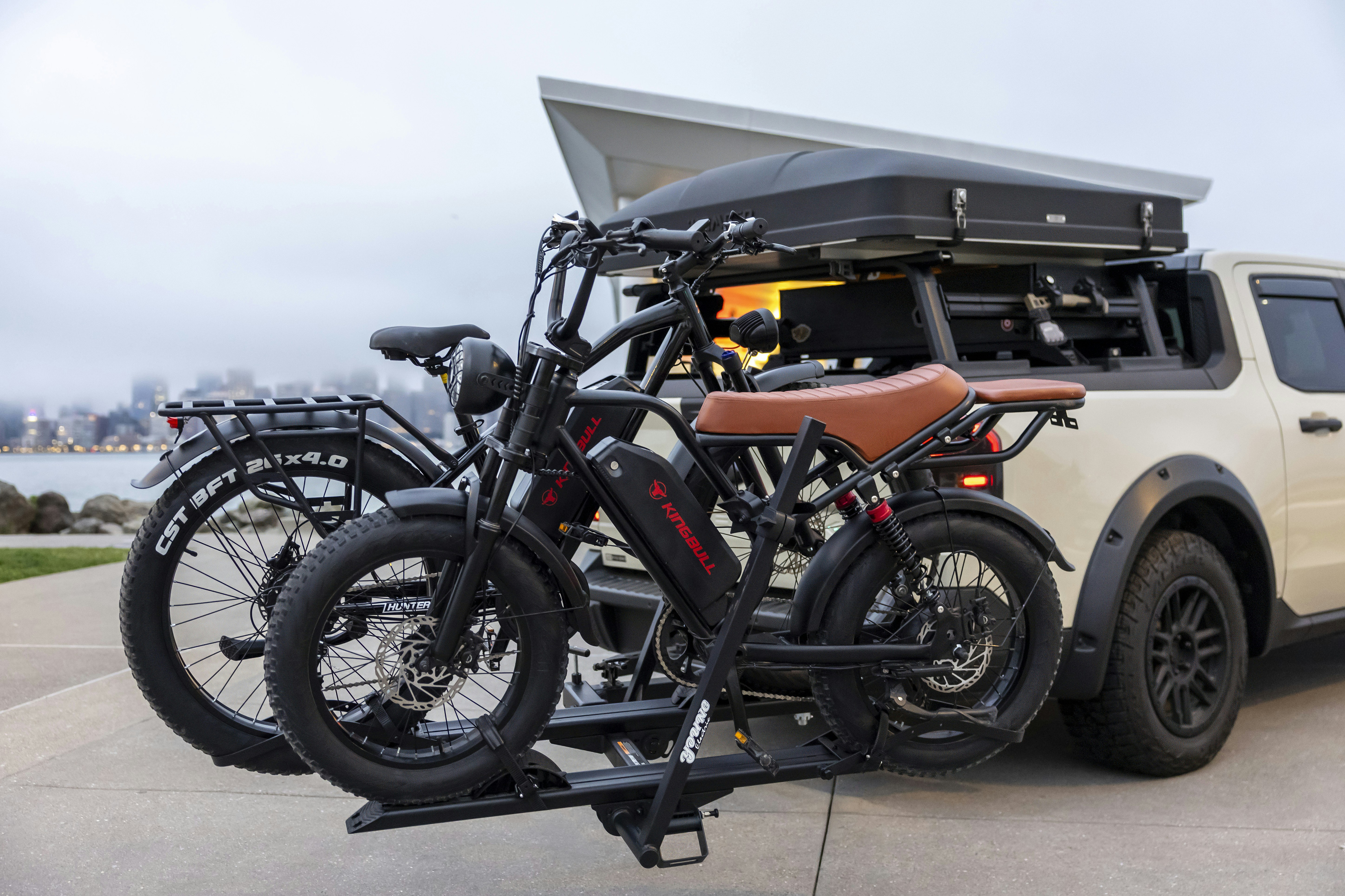 Two e-bikes on a rugged carrier loaded into a pickup bed