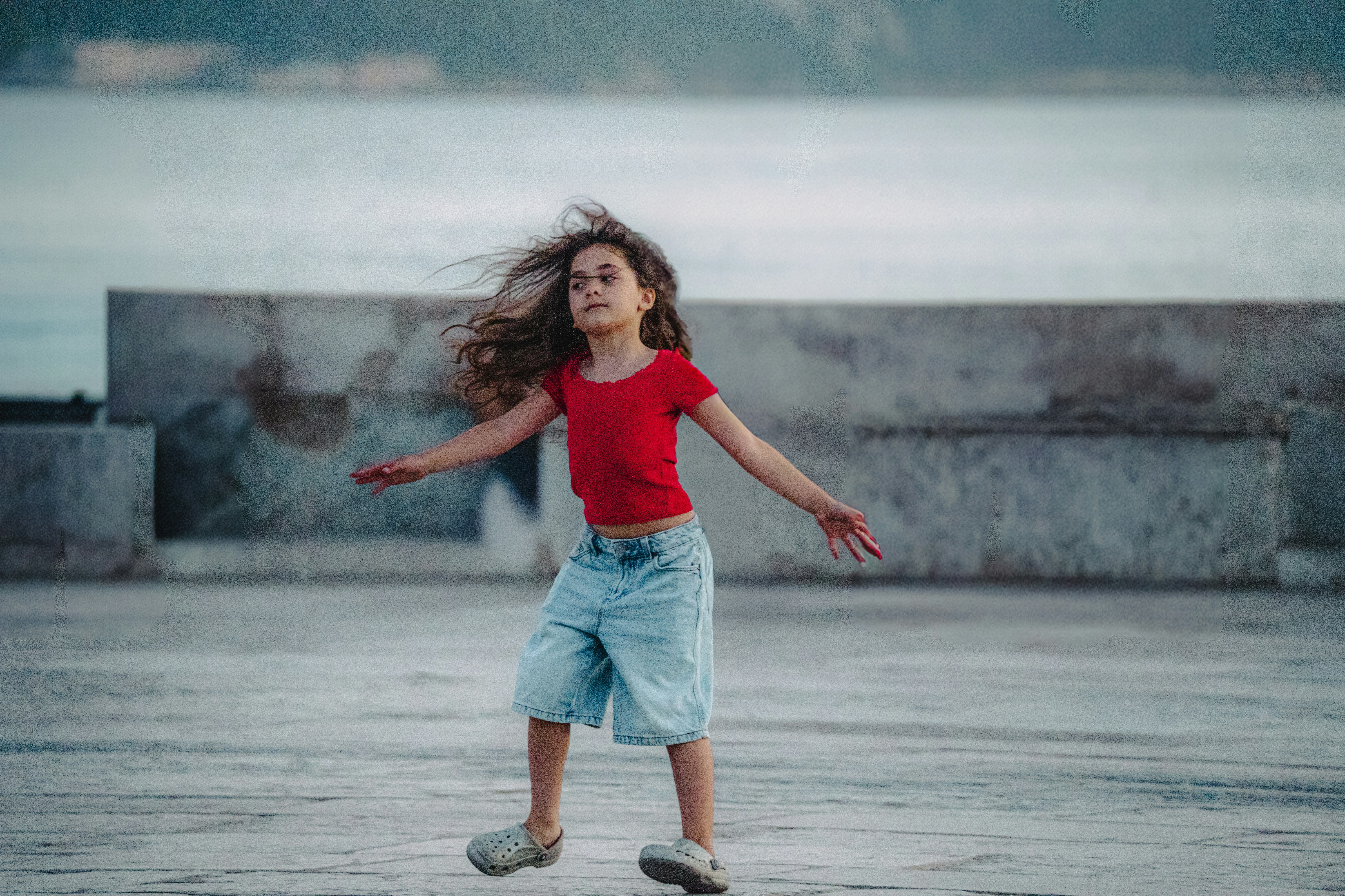 Red-robed Steps: A Girl Dances Across a Wide, Quiet Promenade