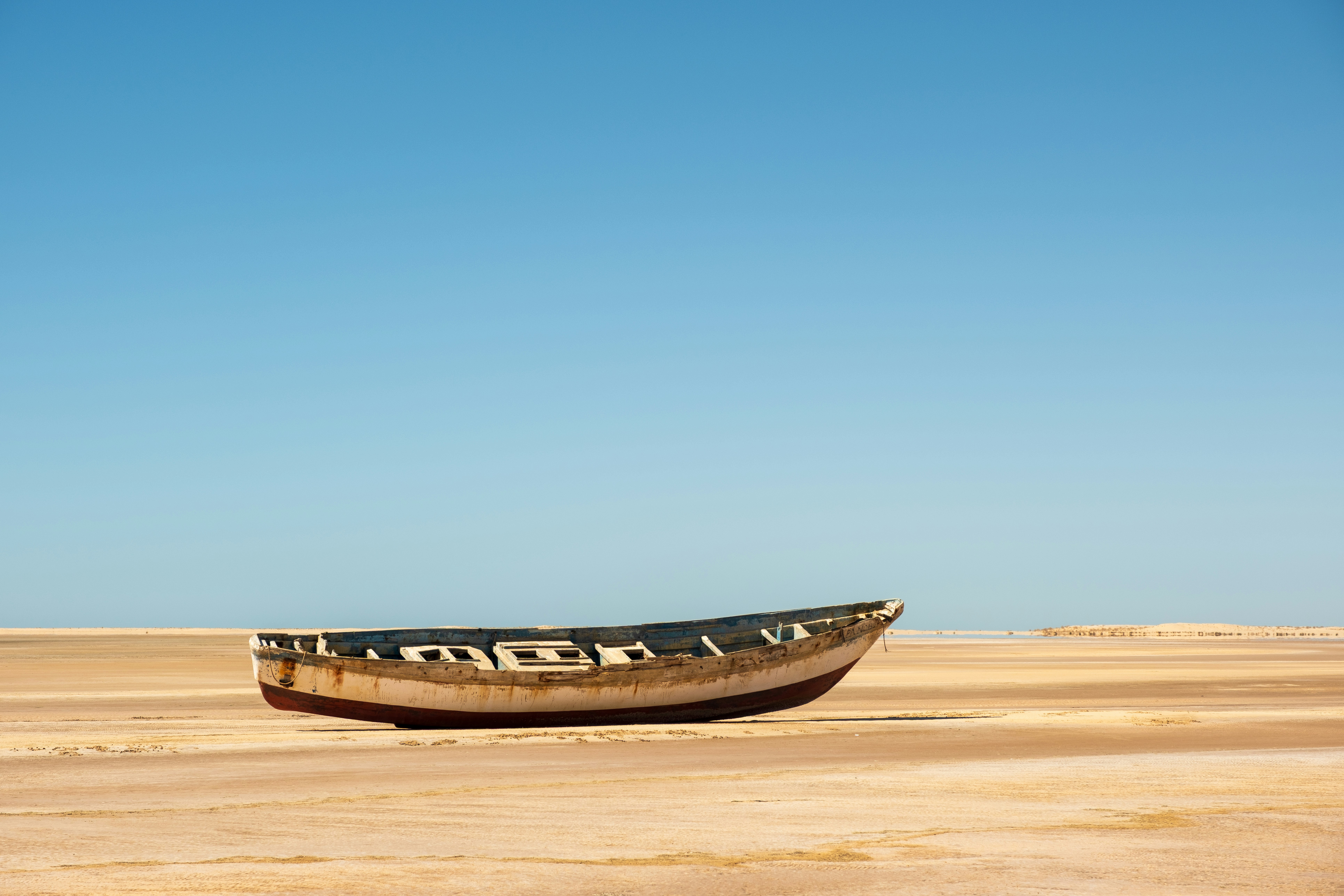 Deserted Husks: A Weathered Boat Resting on Sunlit Sands
