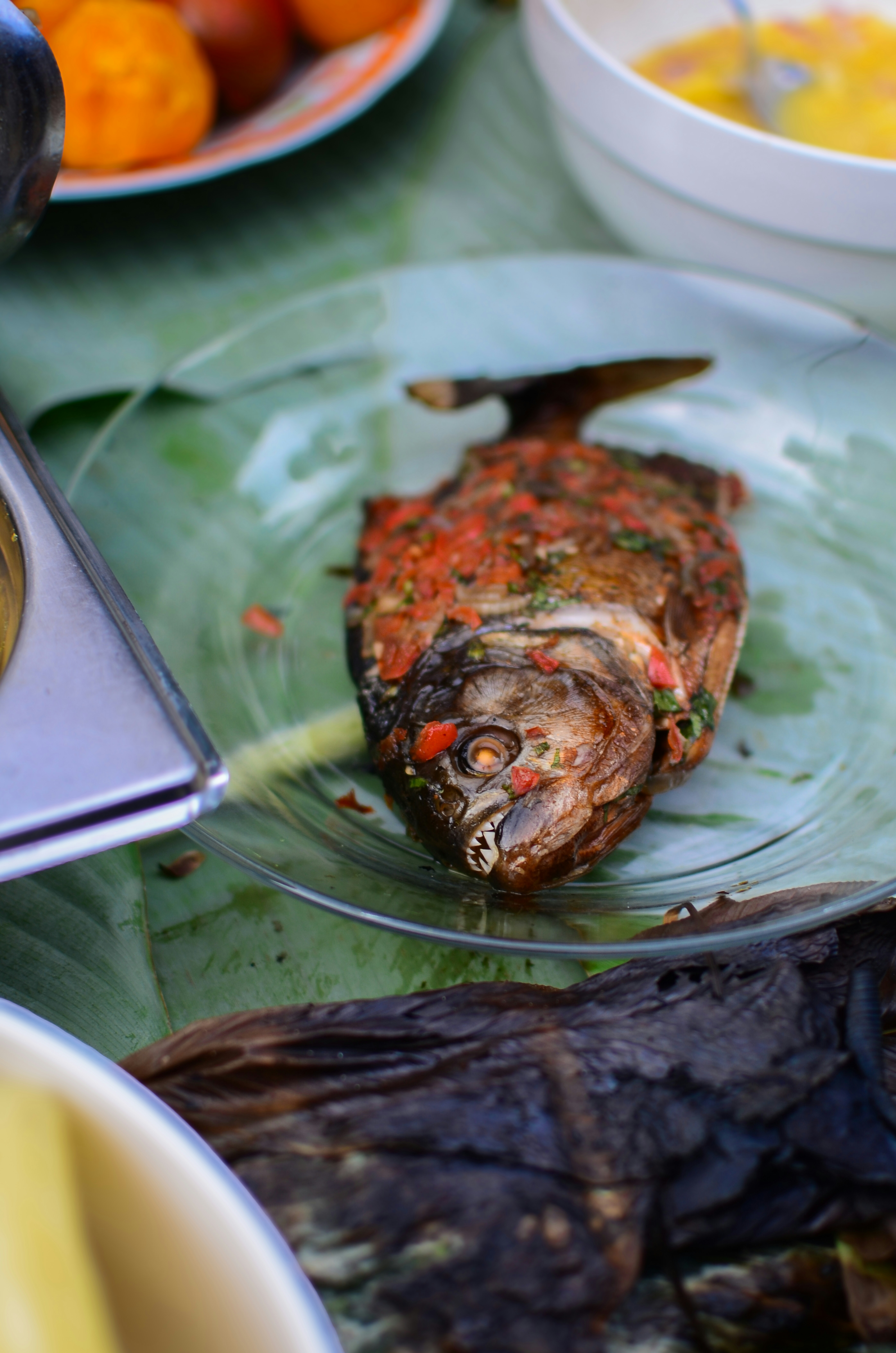 Charred fish centerpiece on a vibrant banquet with citrus and greens