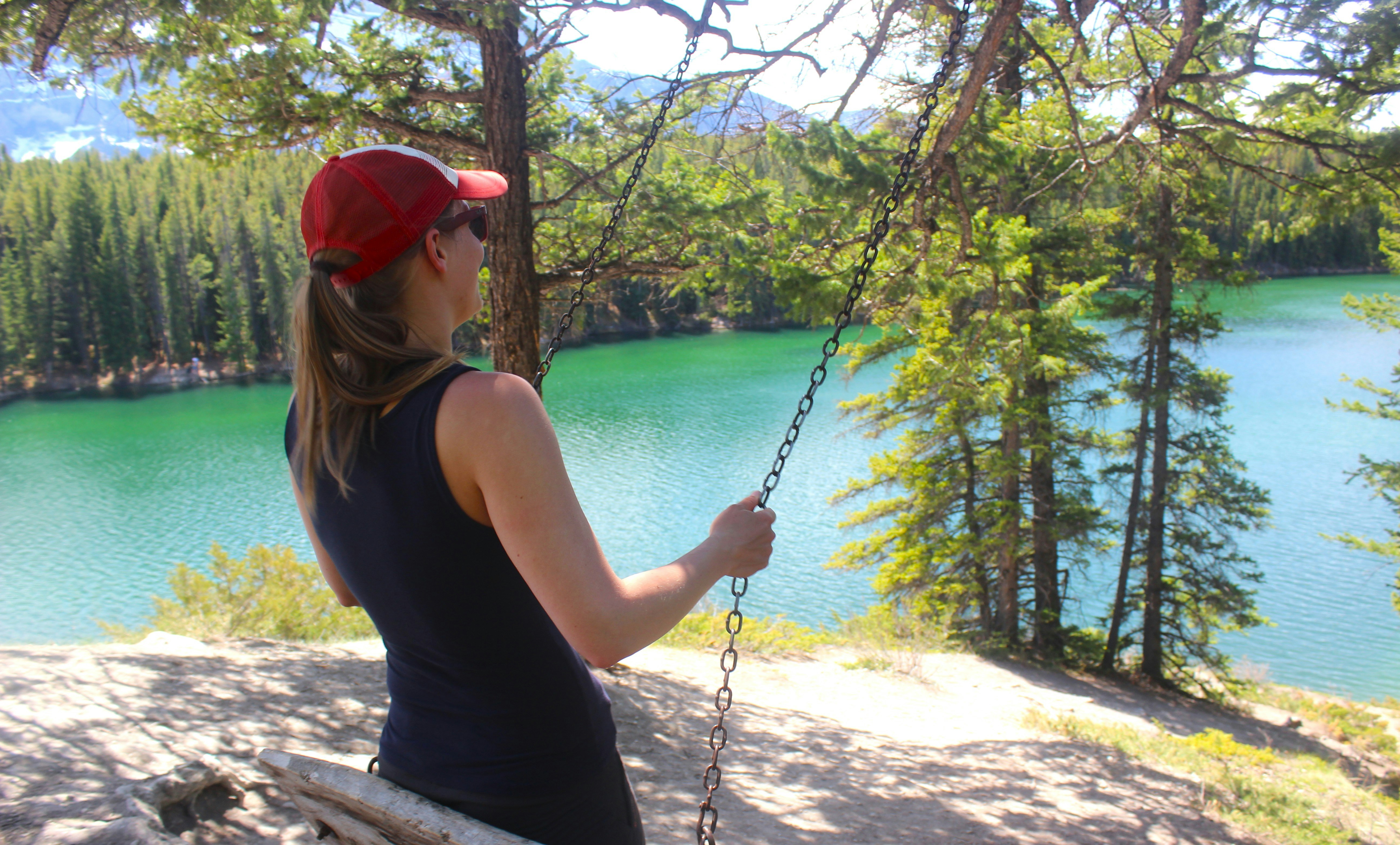 Swinging Moment: A Woman in a Red Cap overlooking a Turquoise Lake