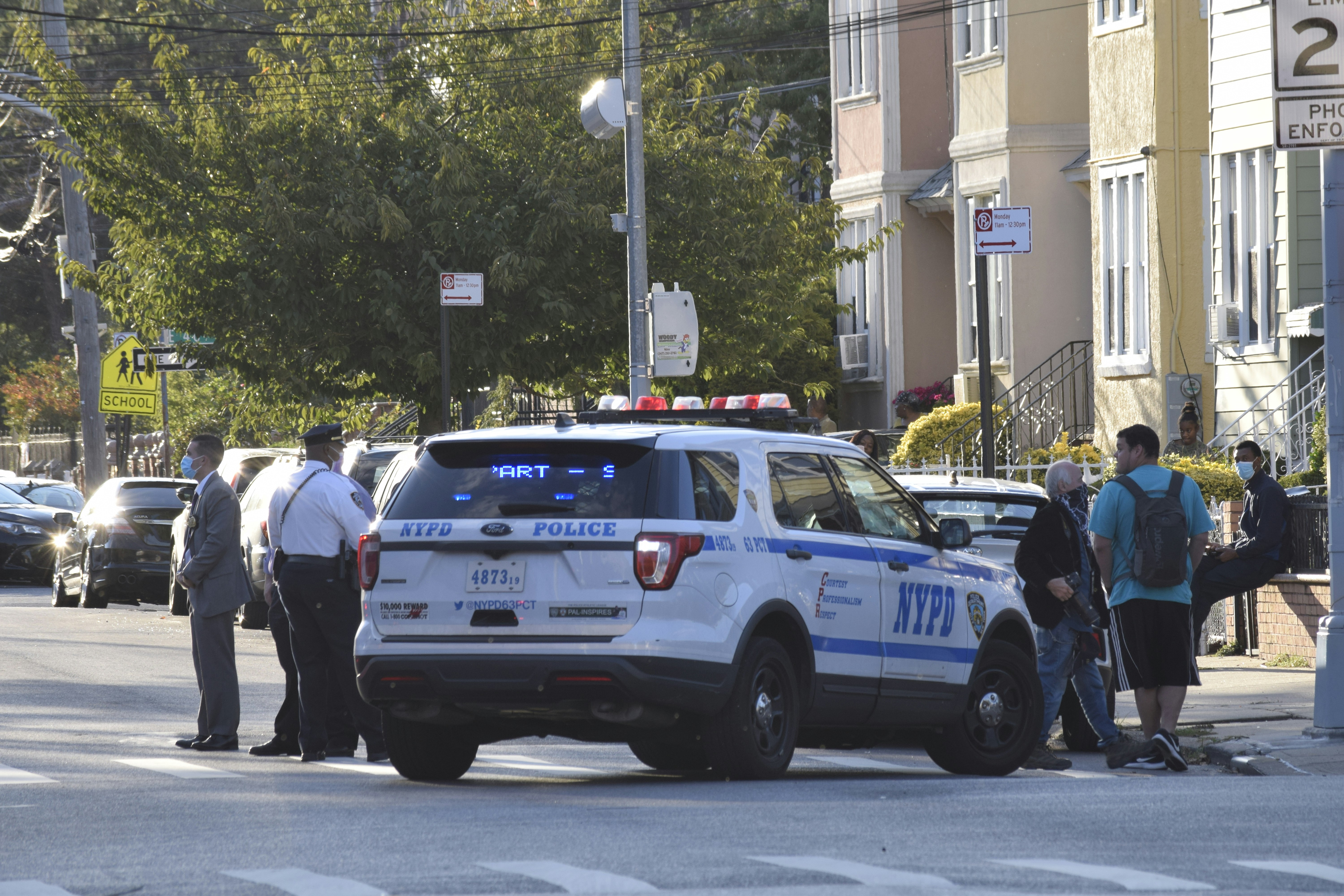 Street Corner Convergence: Police Vehicle and Onlookers in Urban Farewell to Quiet
