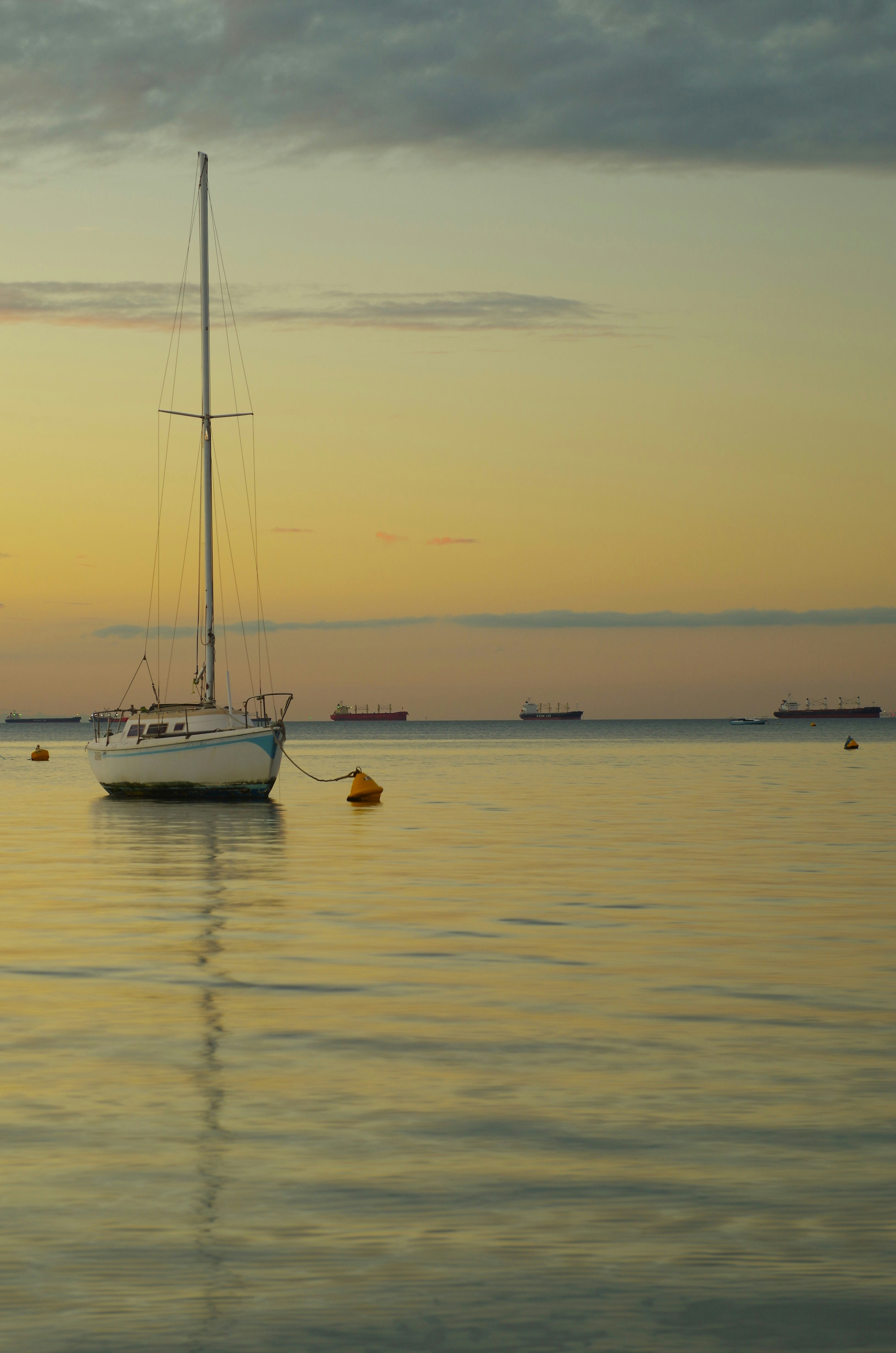 Calm Horizon: A Sailboat Anchored at Sunset