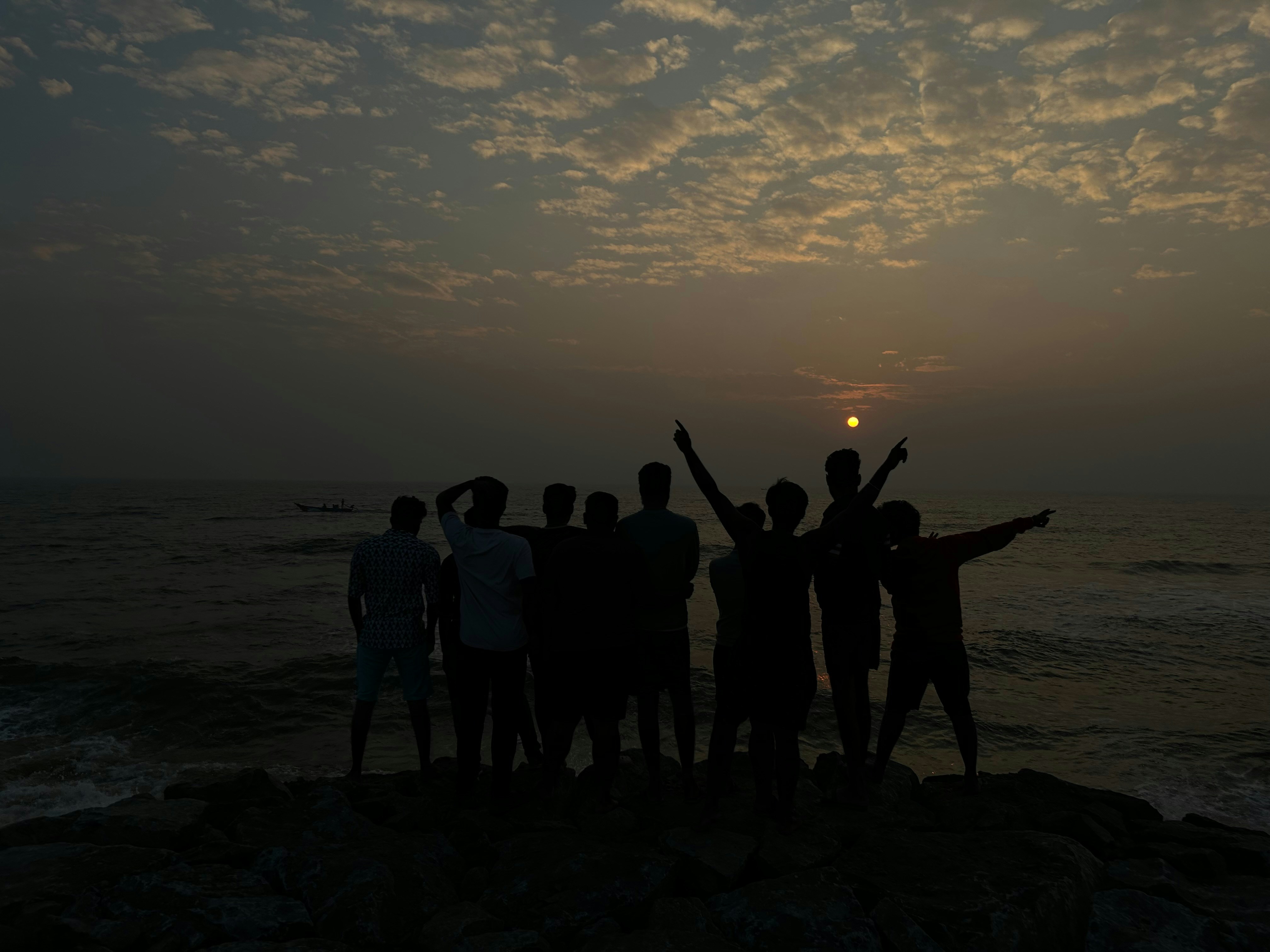  silhouettes on the shore at sunset raising silhouettes toward the horizon