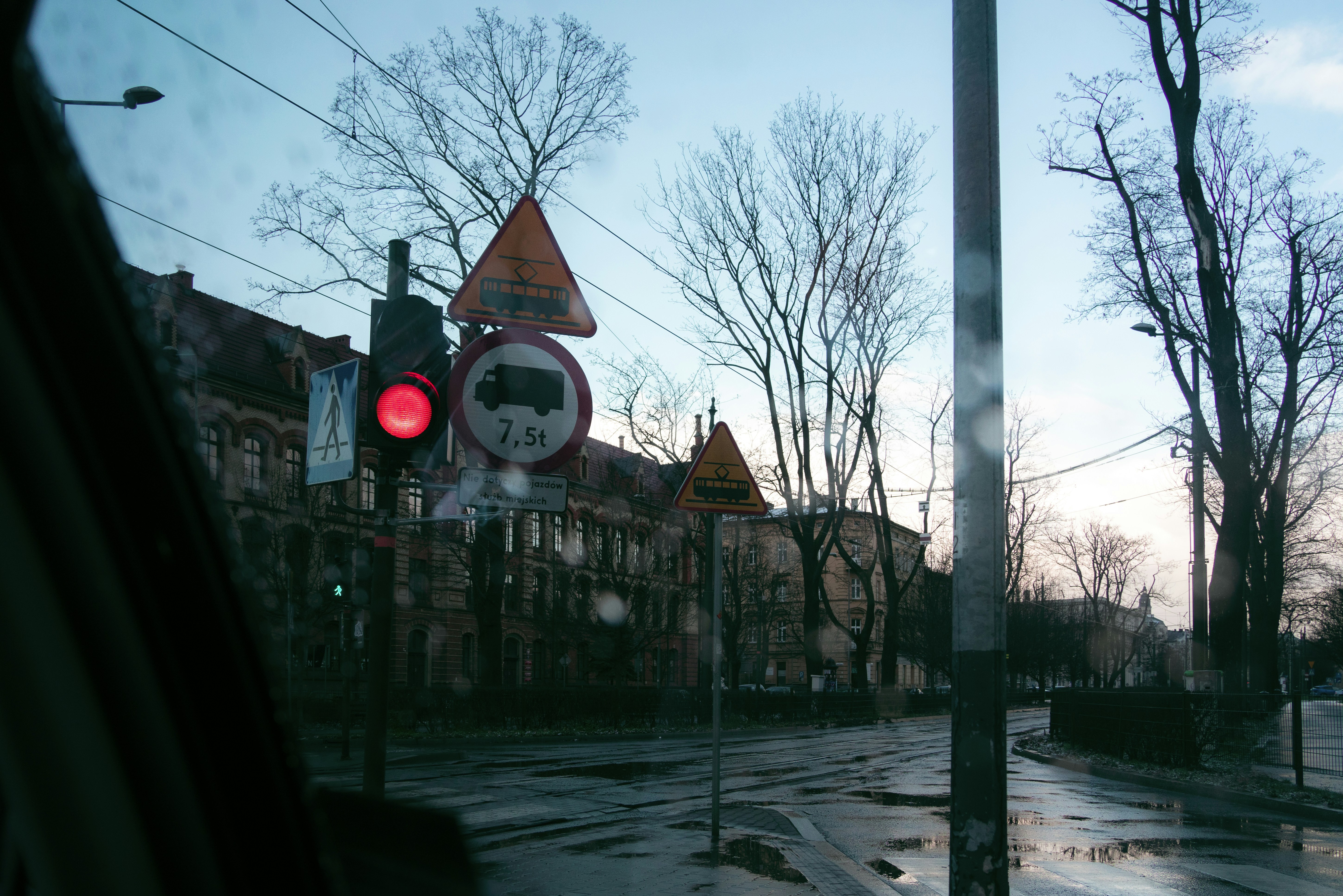 Red Signal at Dusk: Street Scene Through Rain-Slicked Glass