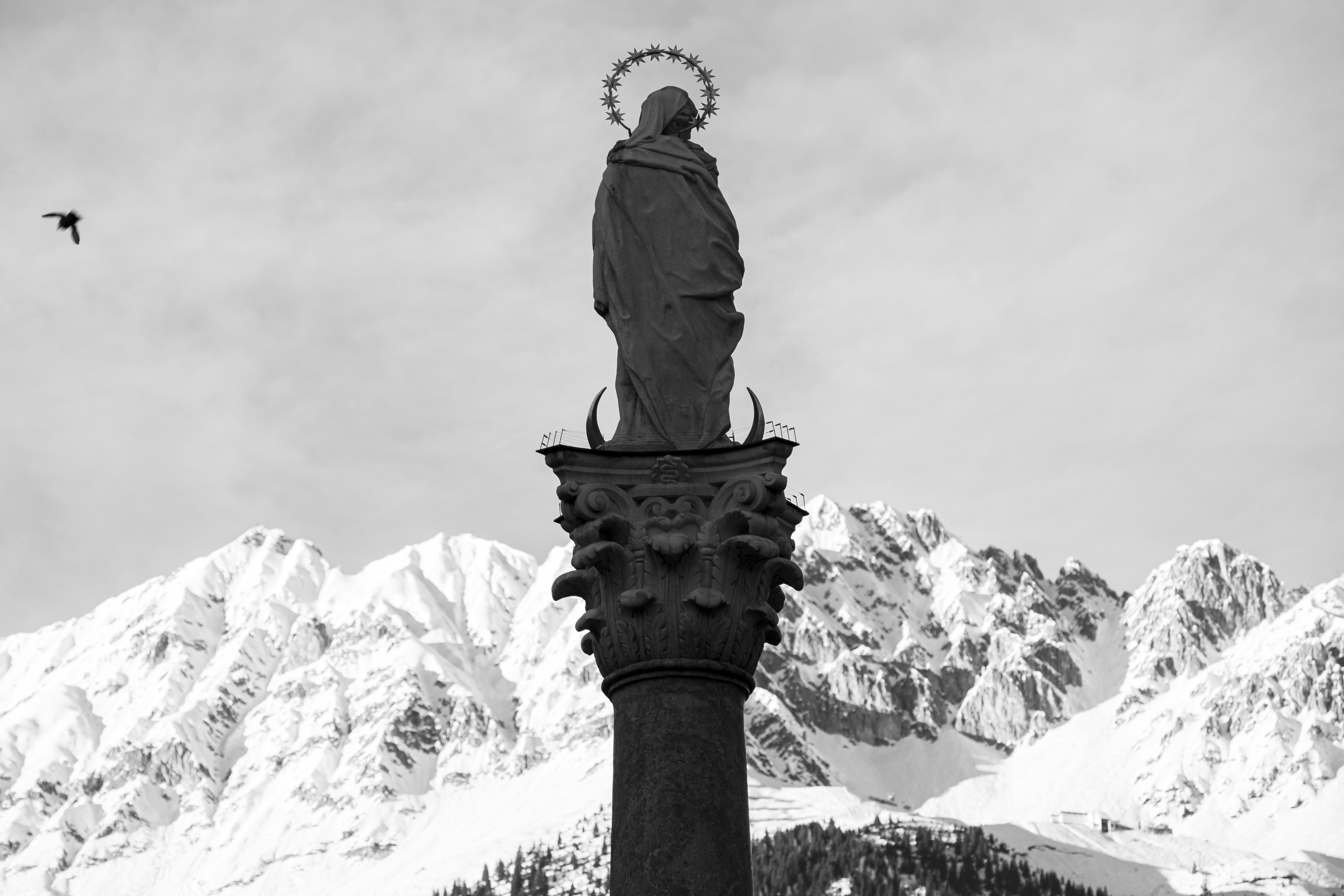Haloed Statue Over Snow-Capped Peaks