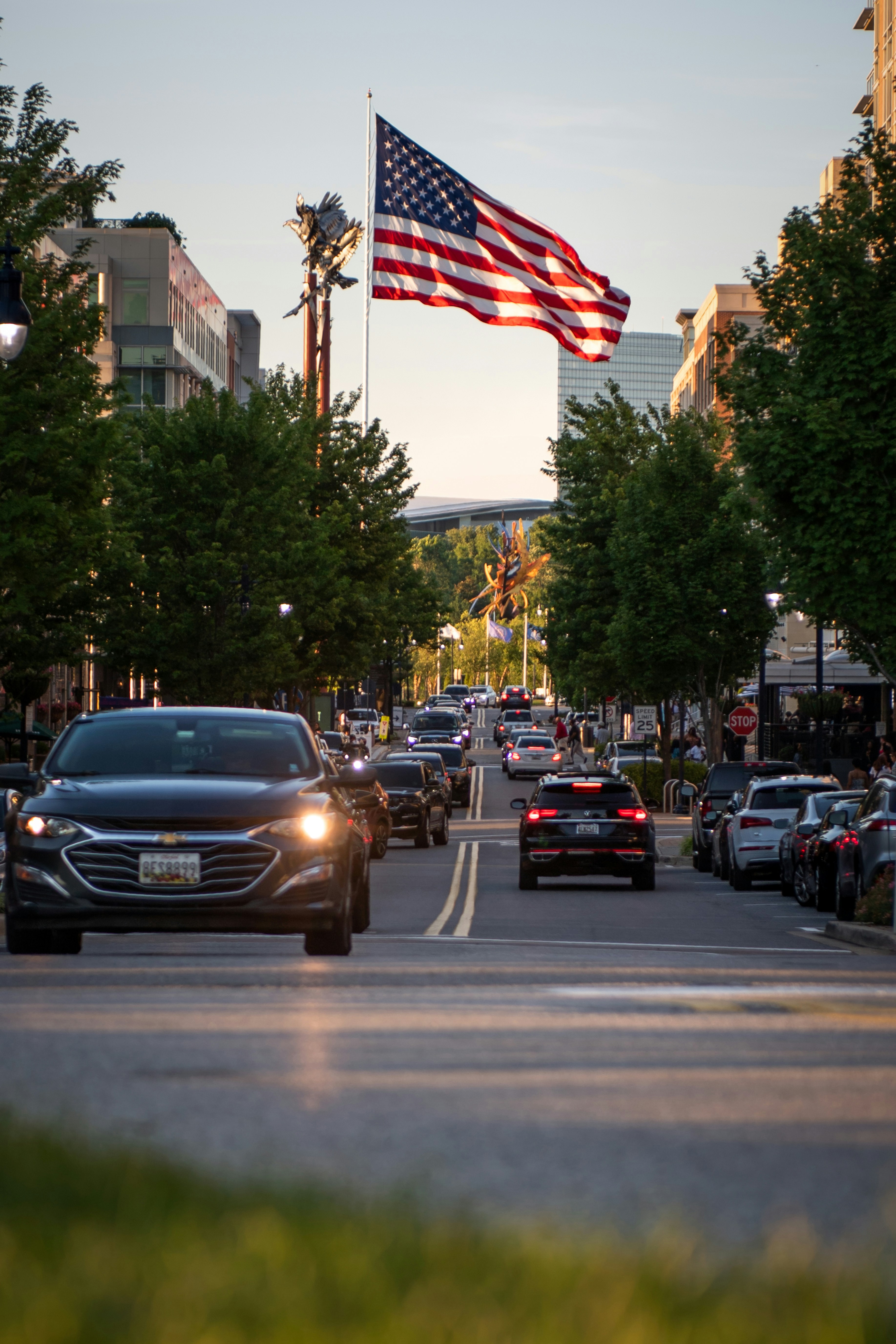 Flag over a city street: late-day bustle beneath a waving banner