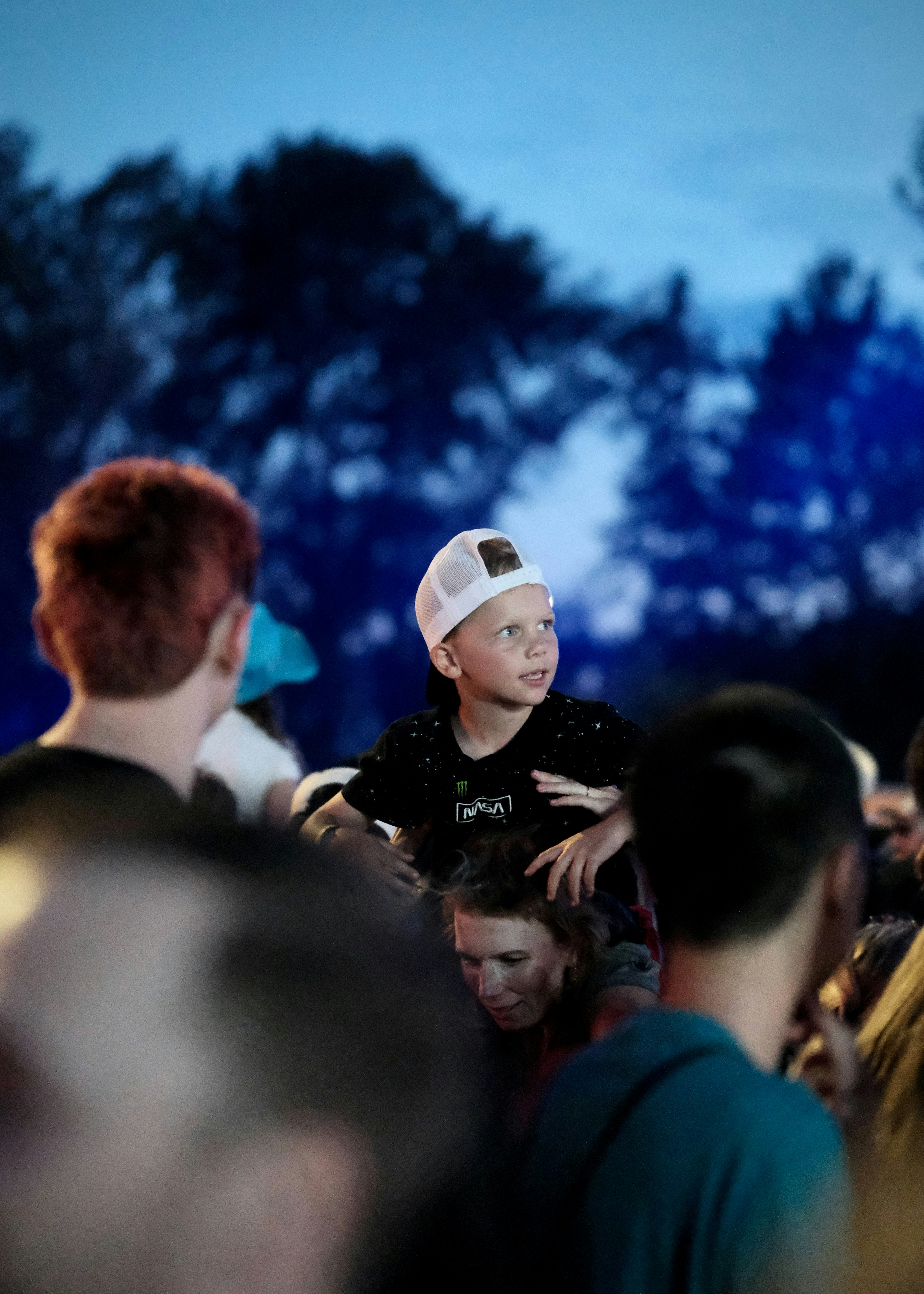Youth in the Crowd: A Kid on Shoulders Under a Dusk Sky