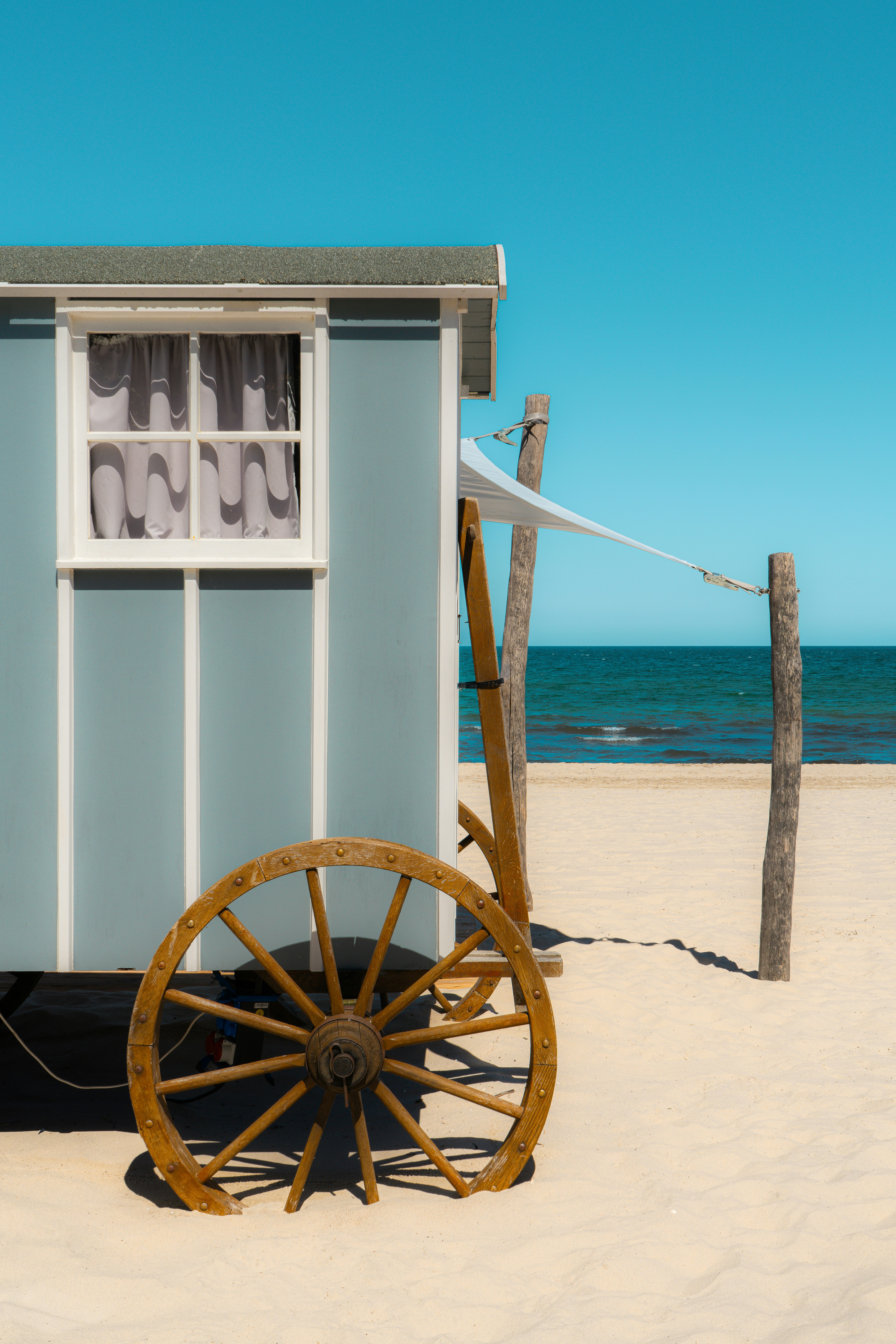 Beach Shack with Weathered Wagon Wheel by Shoreline