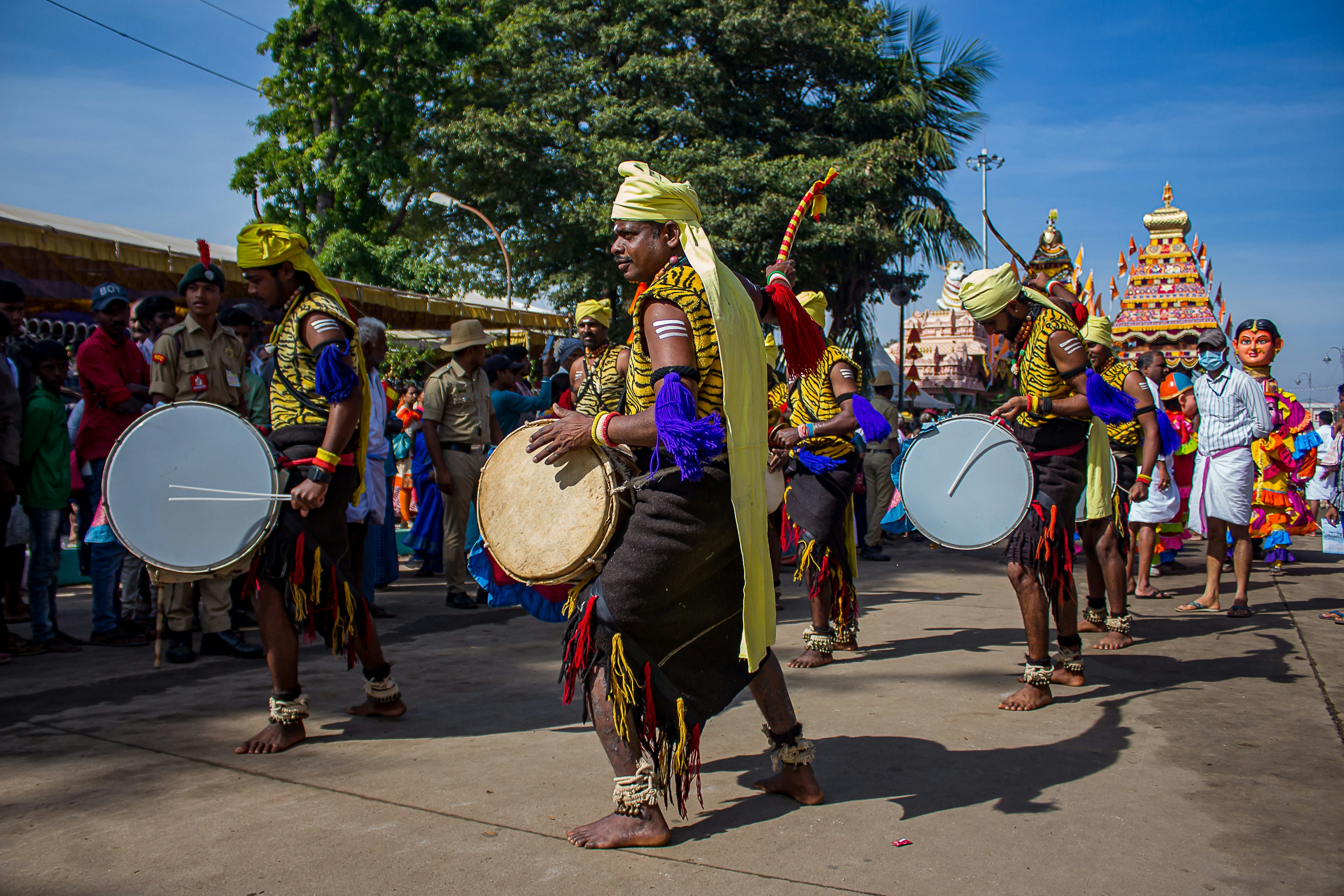 Drummers in Colorful Parade: Rhythmic Steps Beside a Temple