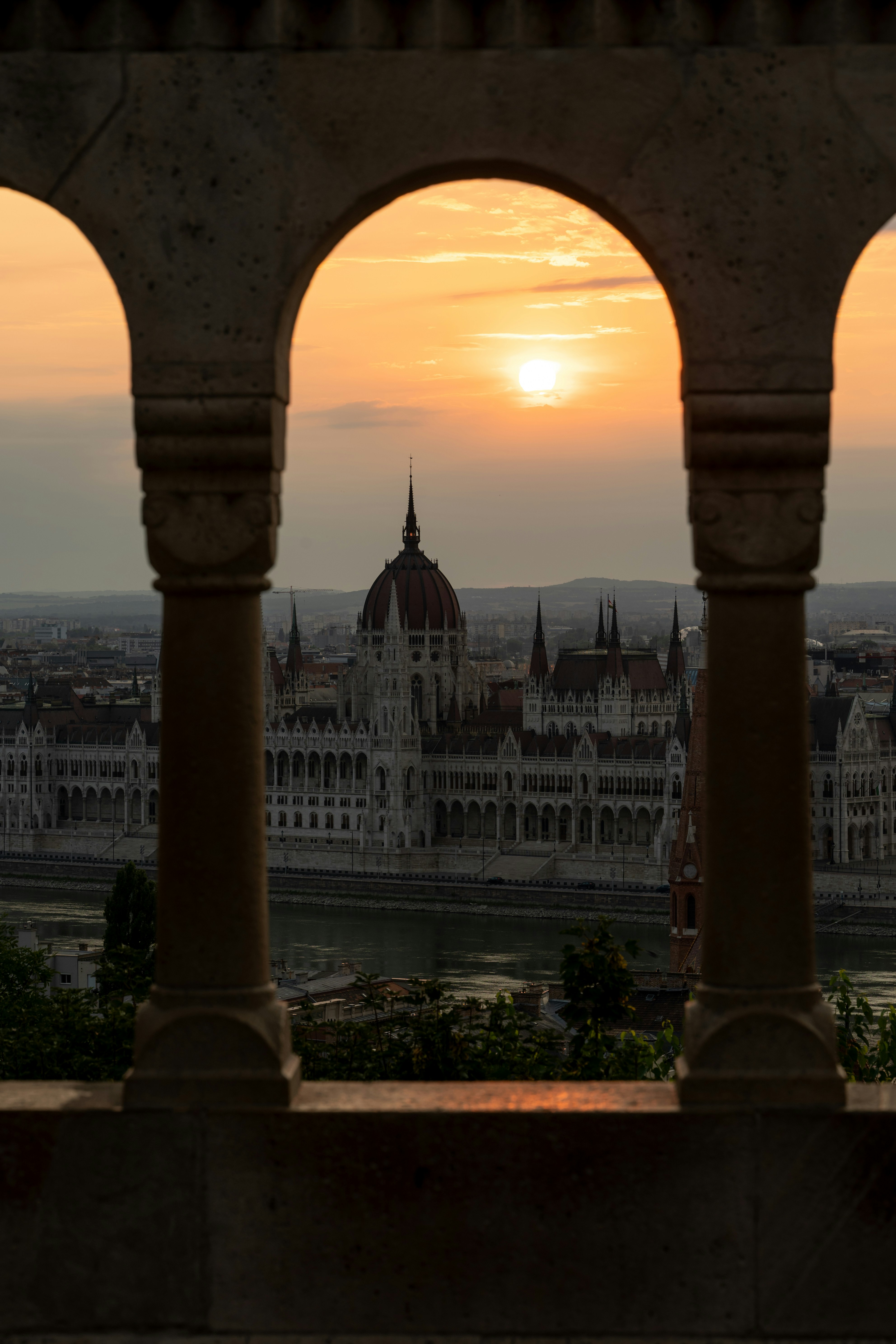 Sunset over Budapest: Parliament framed by stone arches