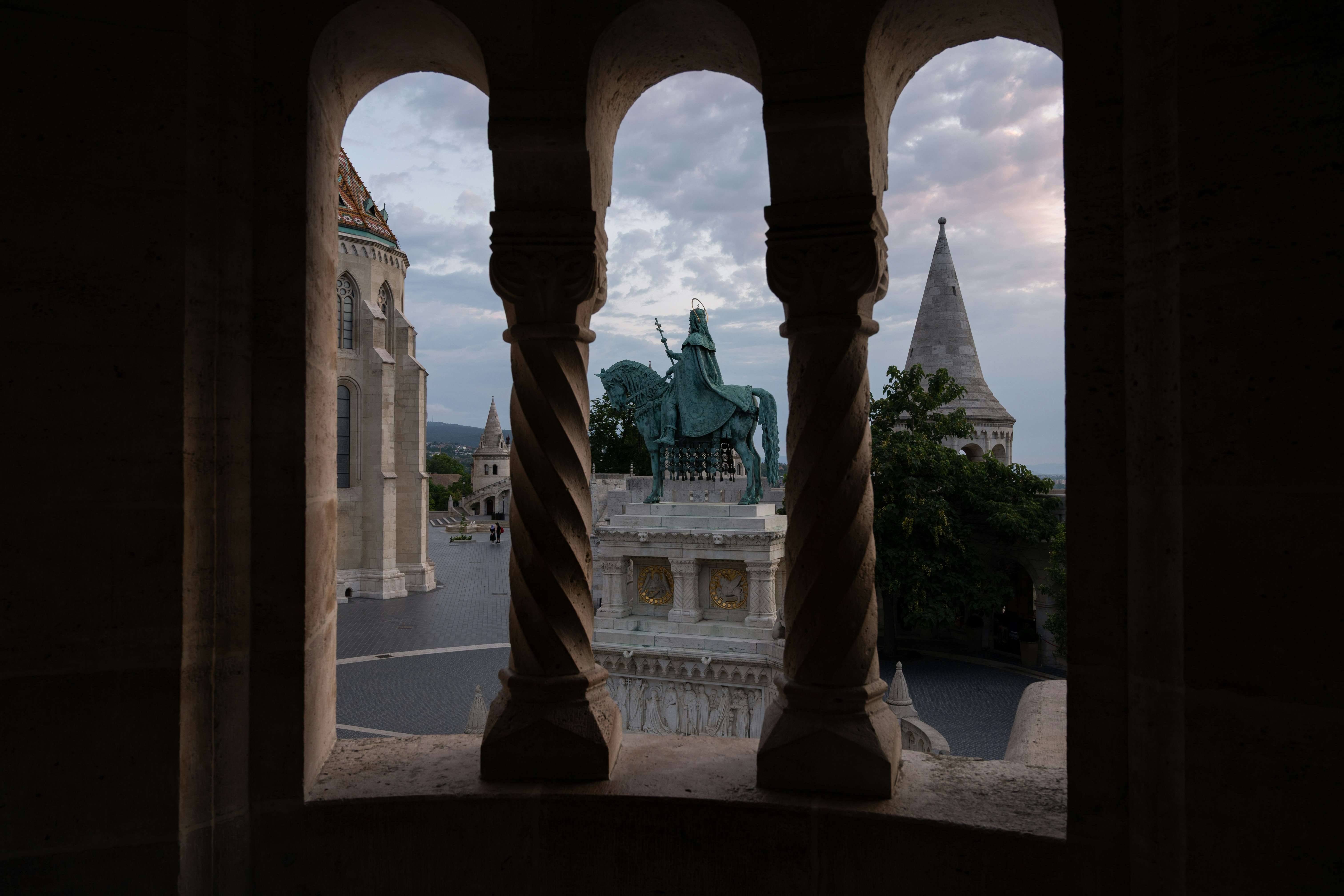 View through ornate arches to a equestrian statue and spired towers