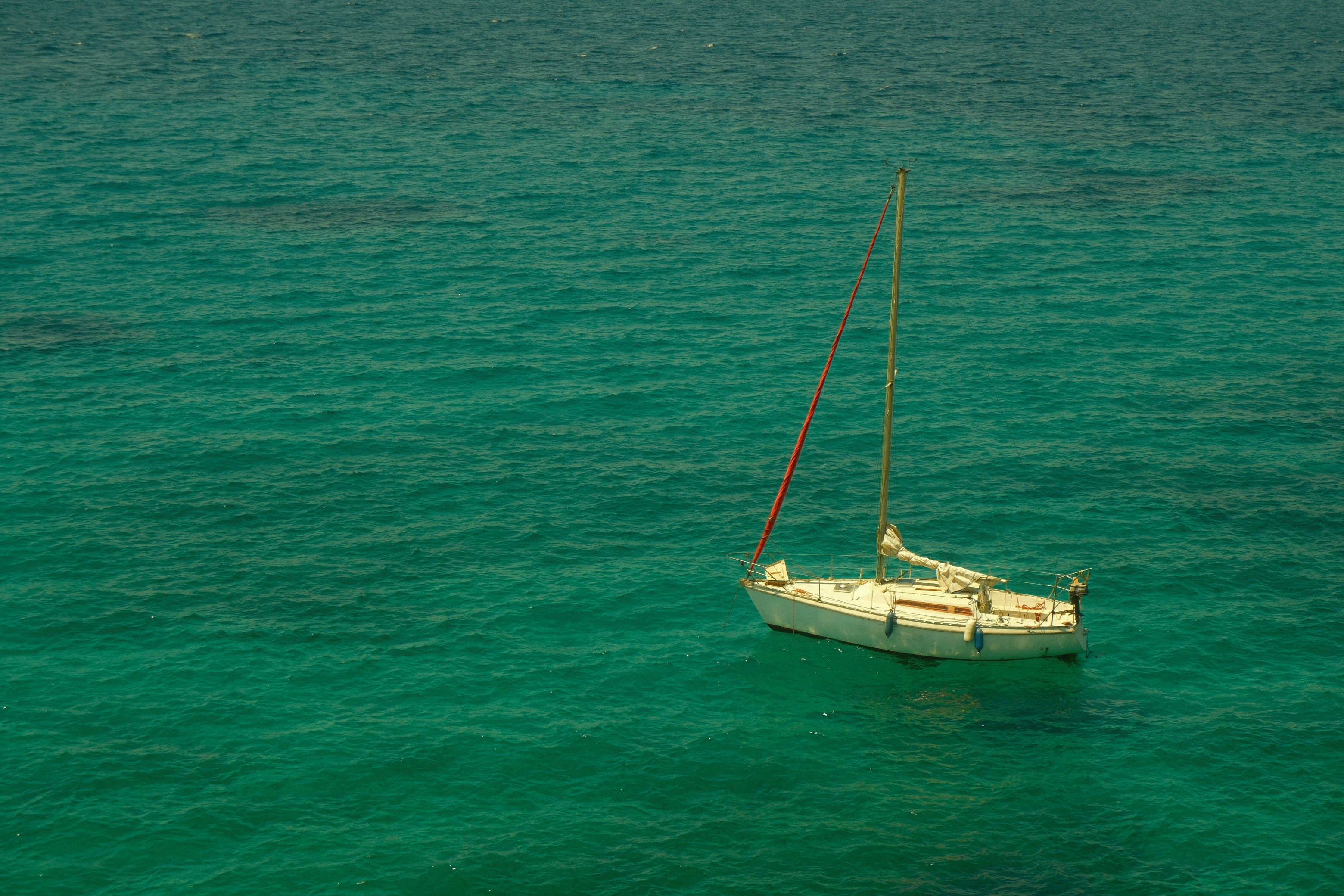  lone sailboat adrift on emerald sea