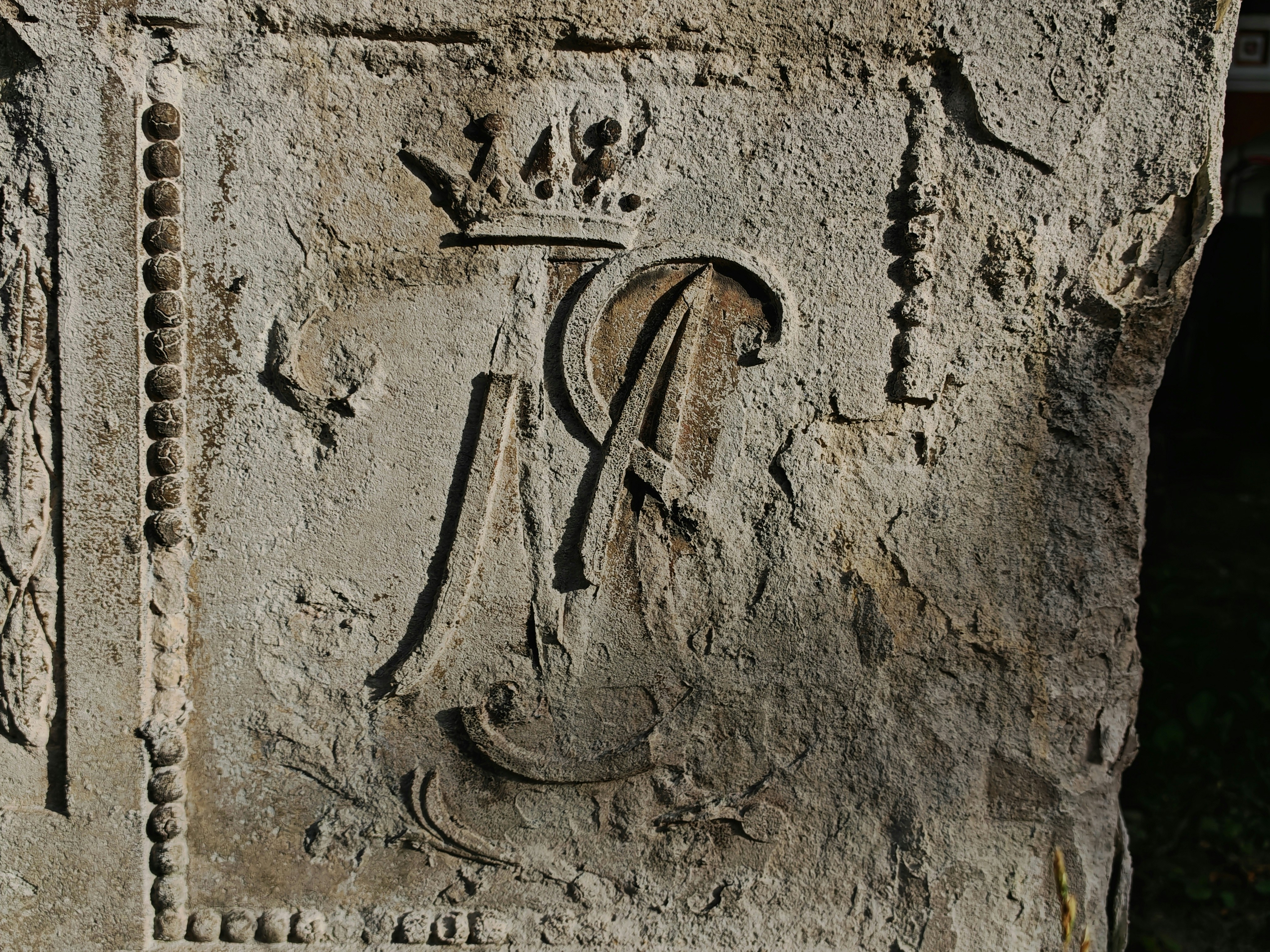 Engraved Monogram Under a Crown: Weathered Stone Carving in Close-Up
