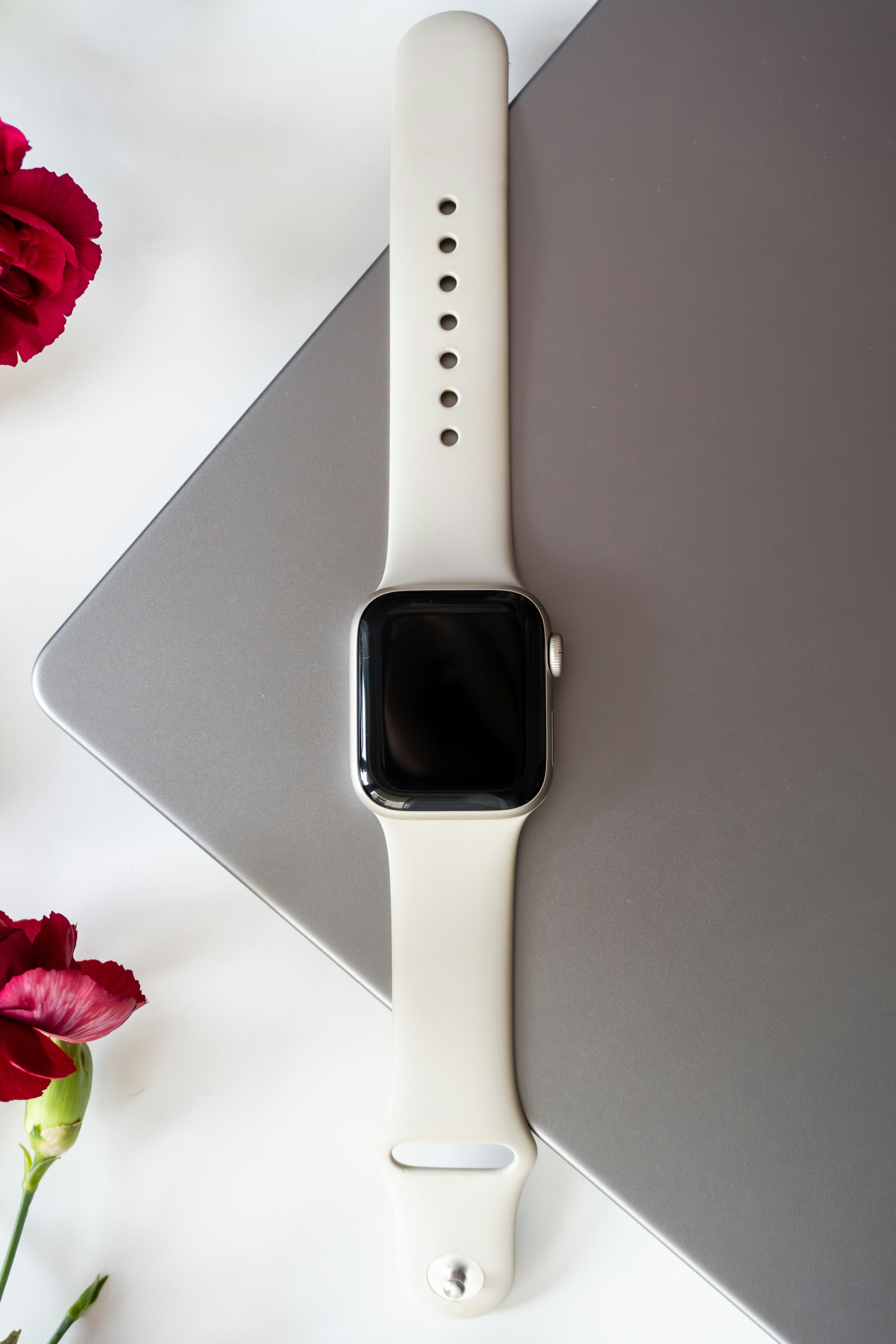 Minimal Tech Elegance: White Apple Watch Resting on a Laptop Corner