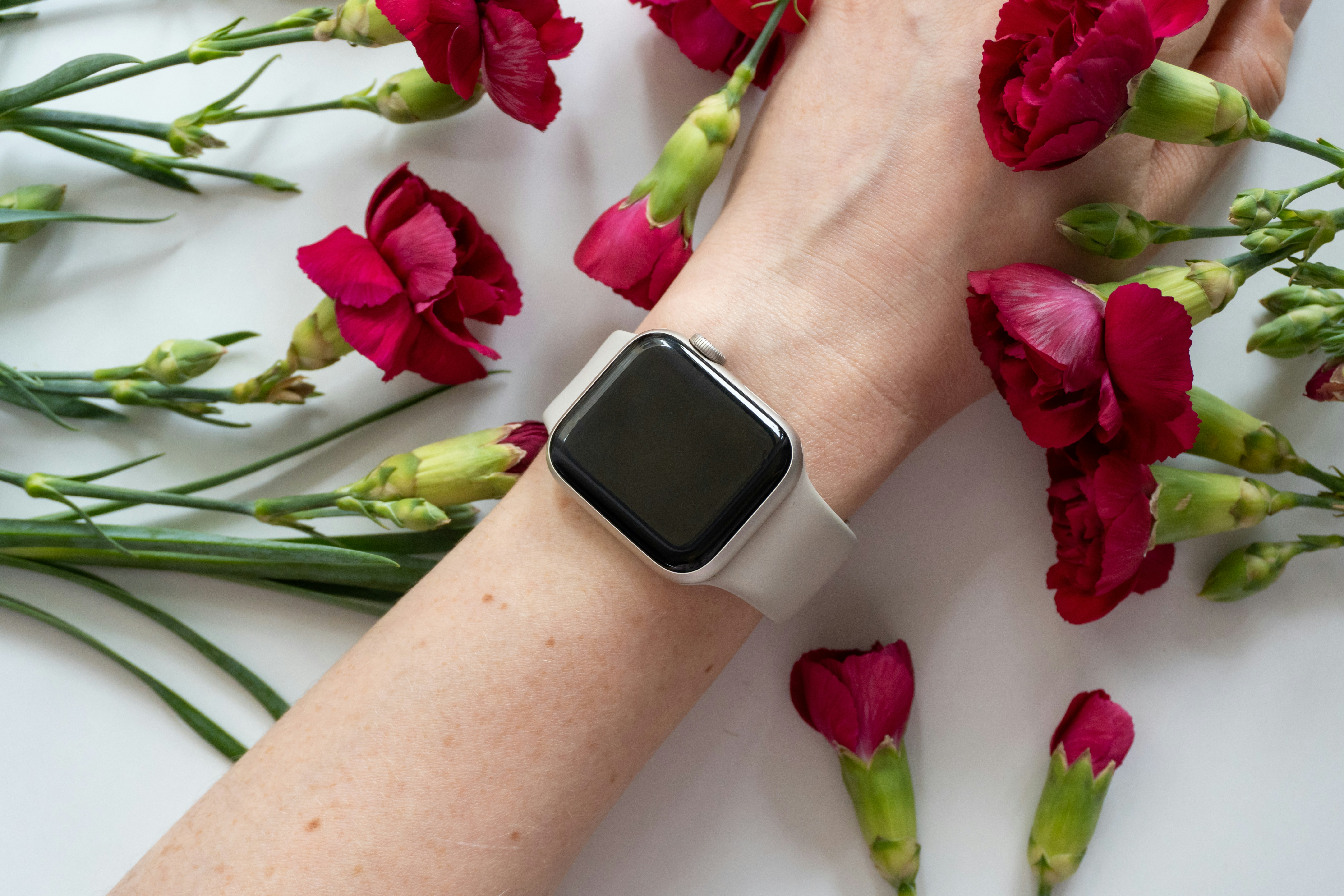 Minimalist Smartwatch Resting Among Pink Carnations