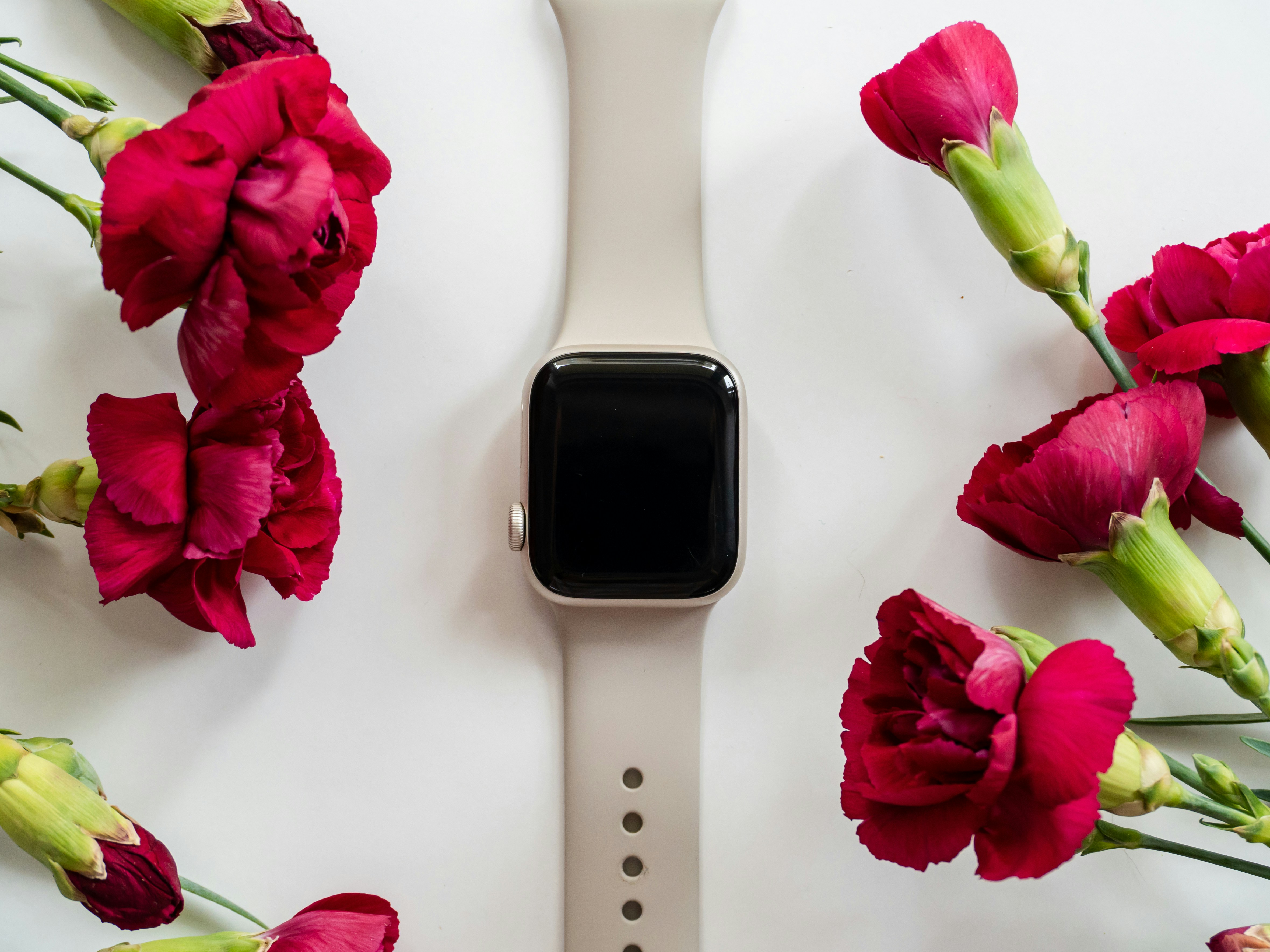 Minimalist Glass: A Beige Smartwatch Centered Among Red Blooms