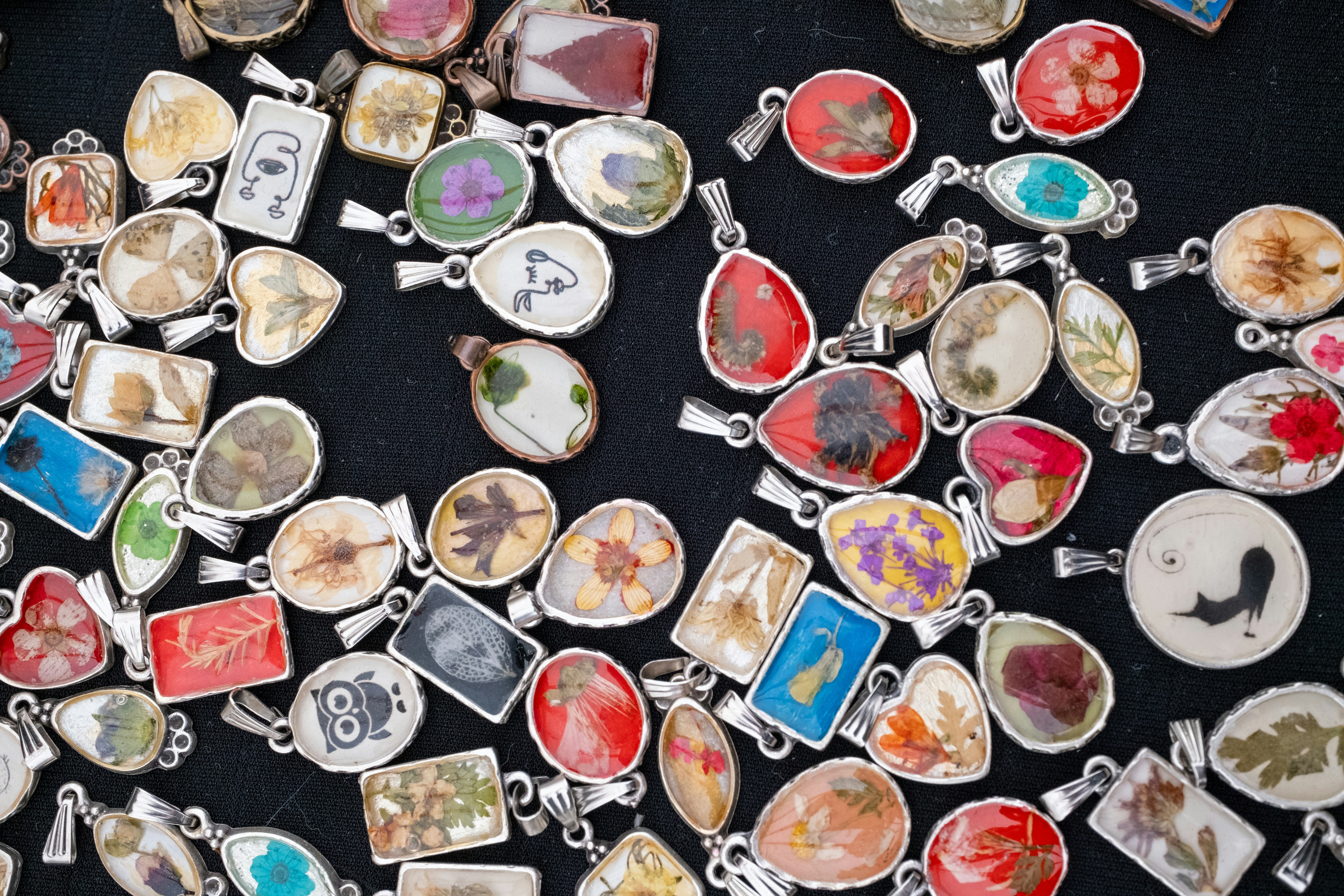 A Sea of Tiny Portraits: Colorful Pendants Scatter in a Dark Canvas