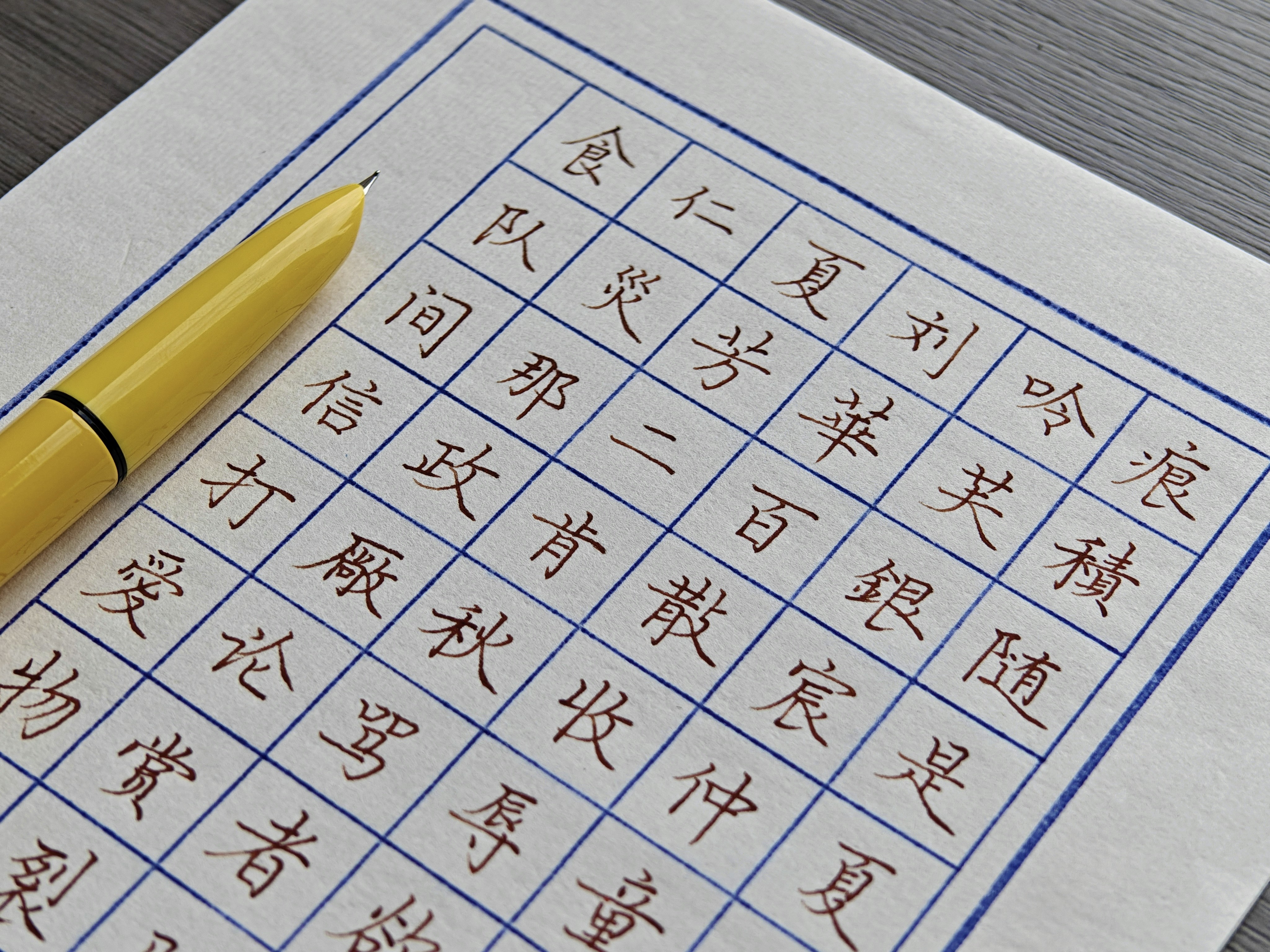 Geometric Calligraphy: A Yellow-Tipped Pen Skims a Grid of Inked Characters