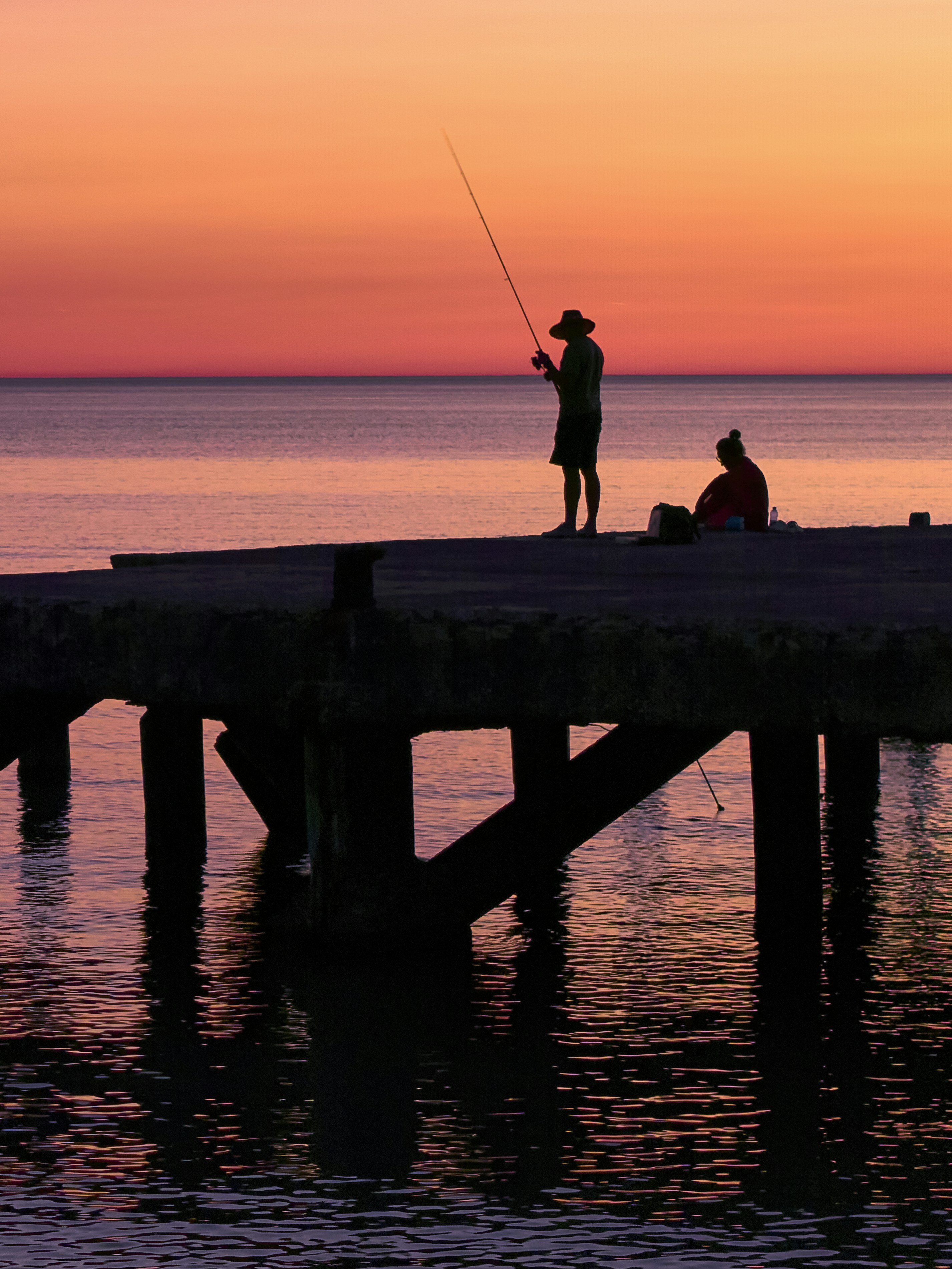 Sunset Pier: A Lone Angler at the Water’s Edge