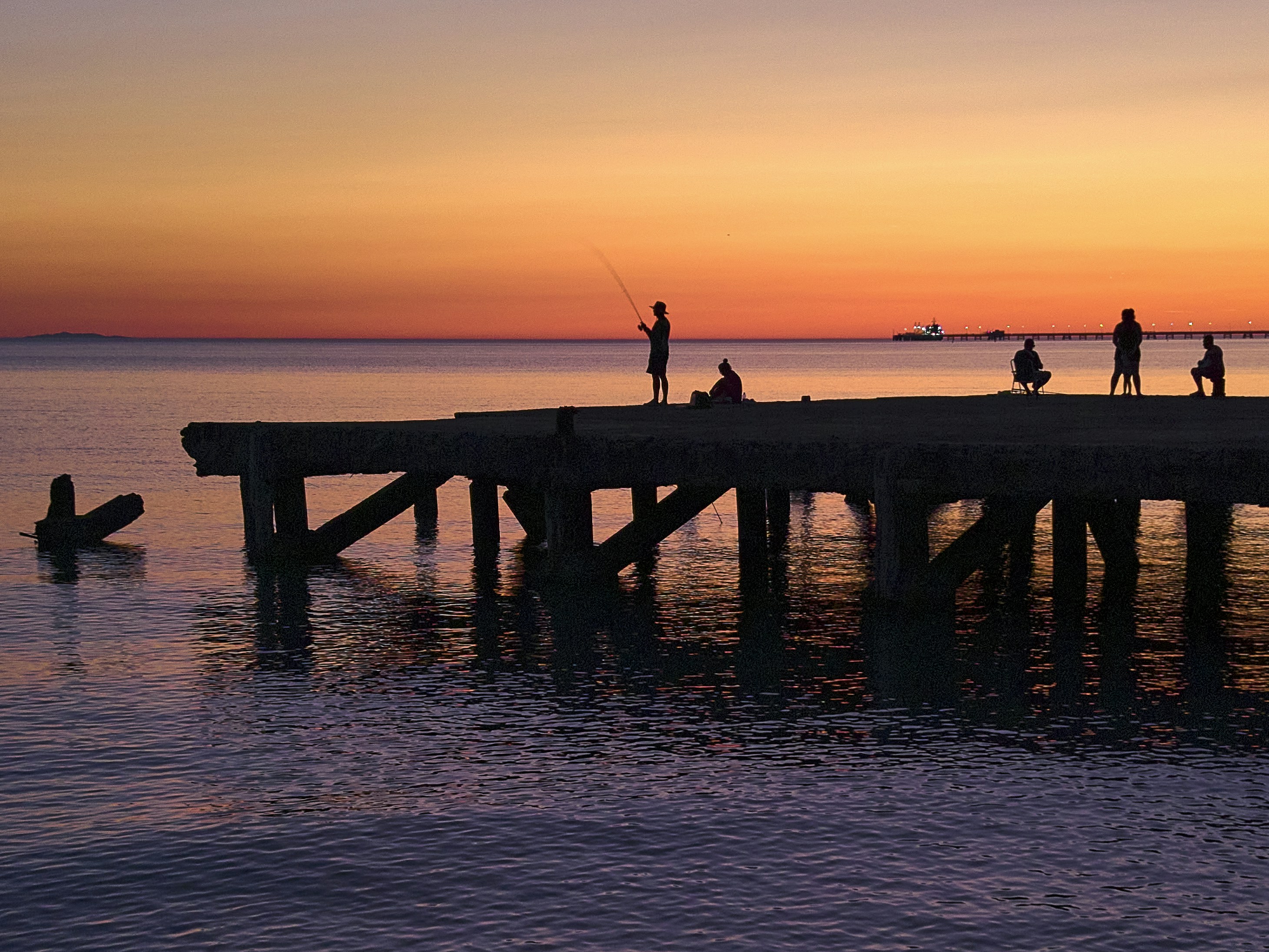 Sunset Pier: Anglers in Silhouette Under a Golden Horizon