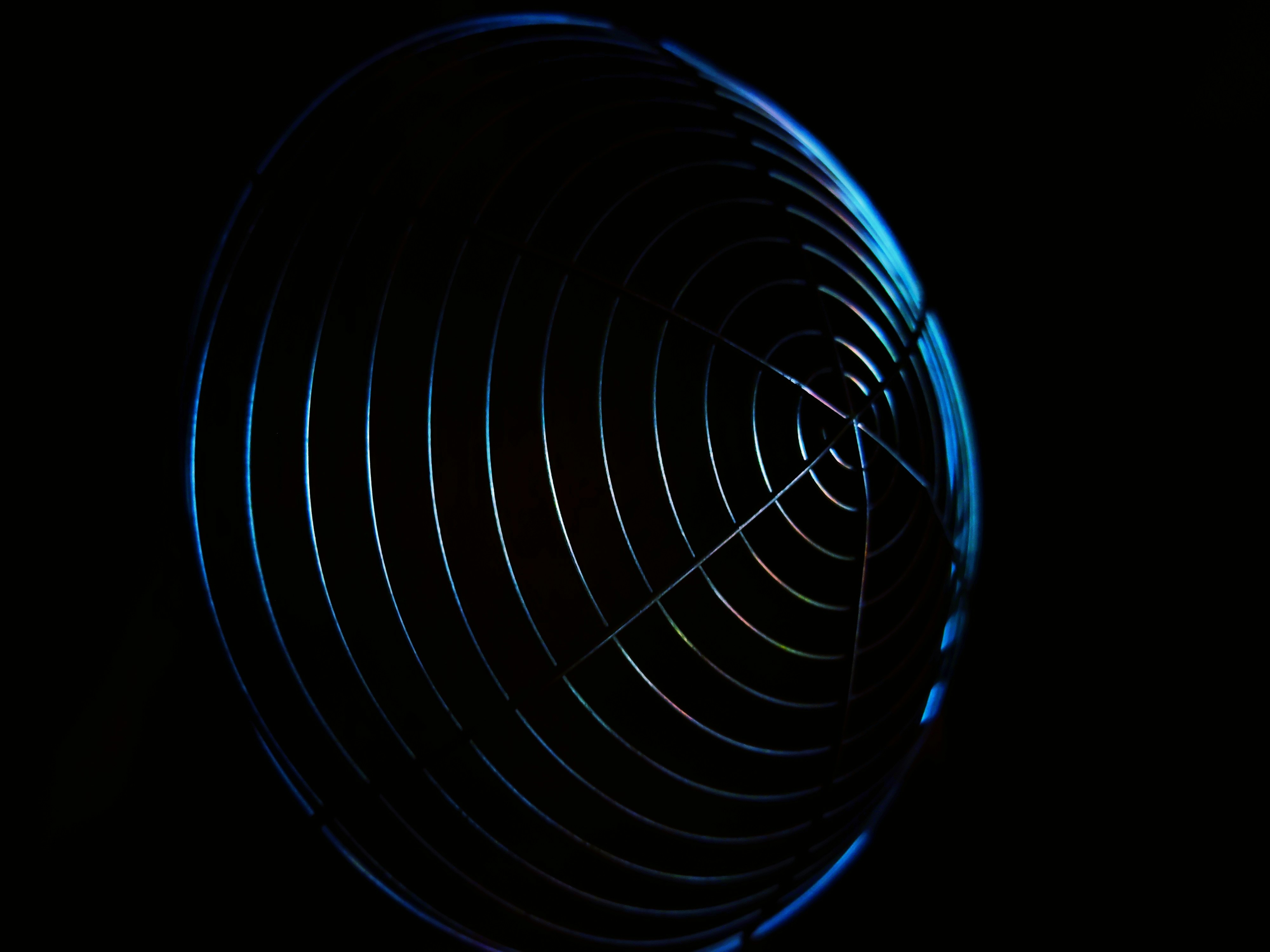 A minimalist, high-contrast abstract shot featuring glowing blue neon light reflecting off concentric circular metallic wires against a pure black background. Perfect for dark mode wallpapers, sleek user interface backgrounds, and modern tech-themed designs & OLED type displays.