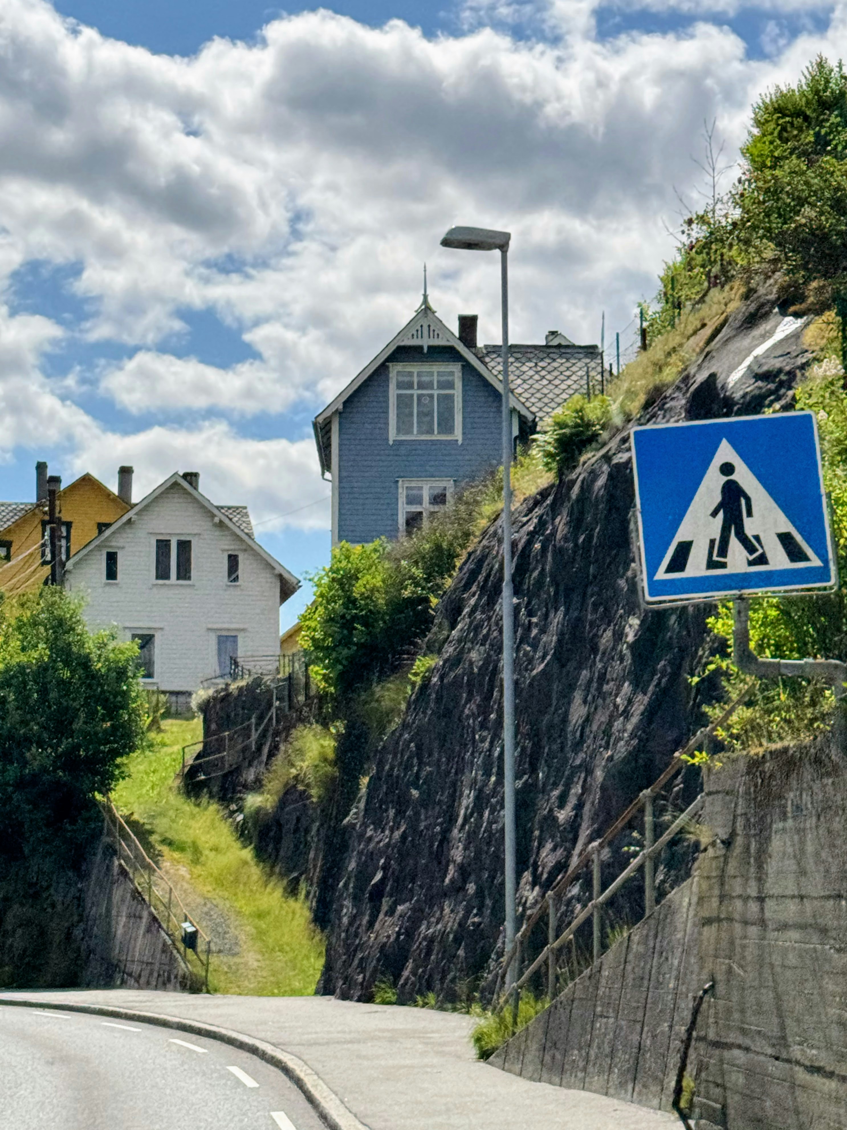 Blue House on the Cliff: A Quiet Street Under a Pedestrian Crossing Sign