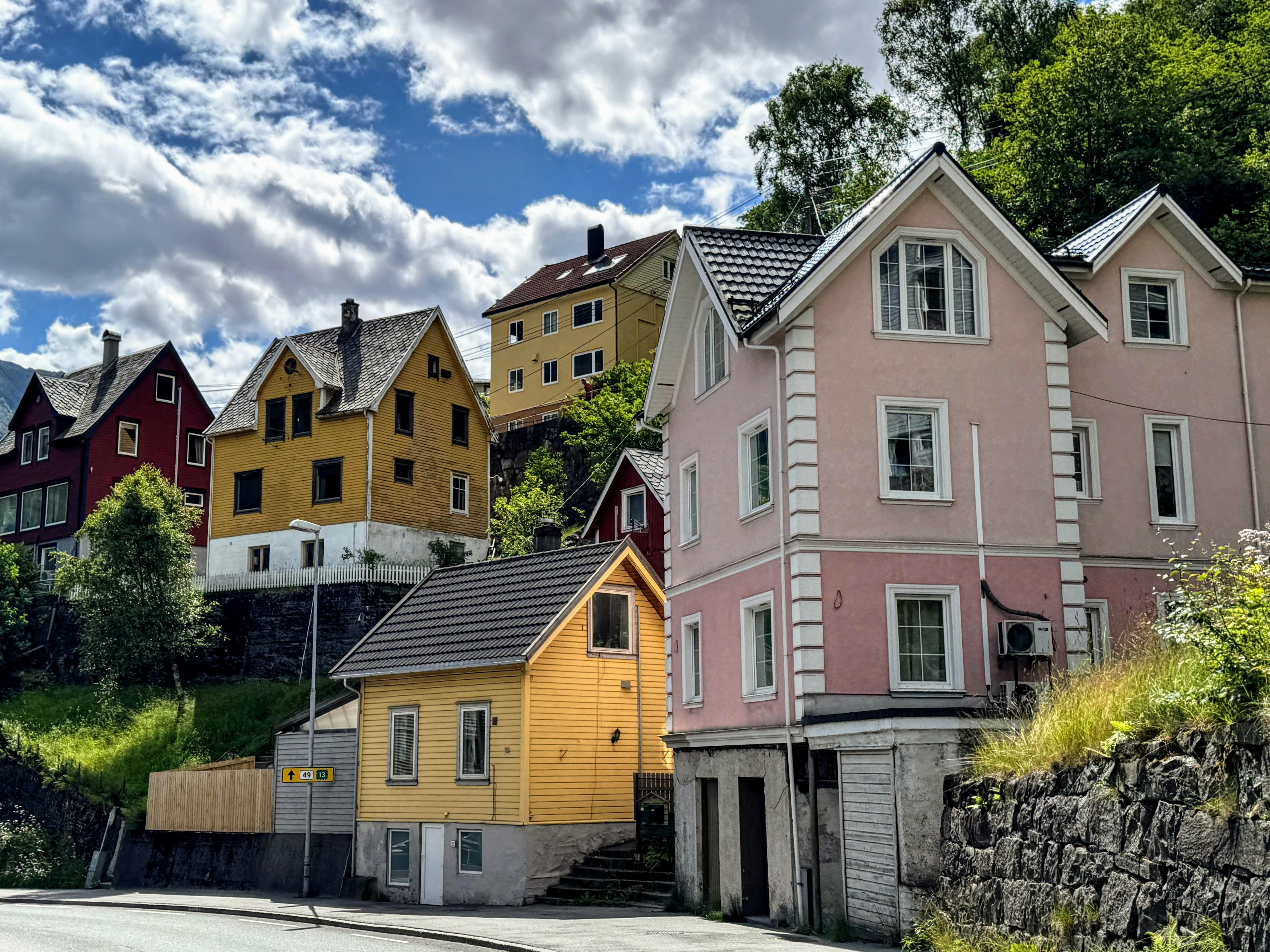 Colorful hillside houses cling to a rocky slope under a bright Nordic sky
