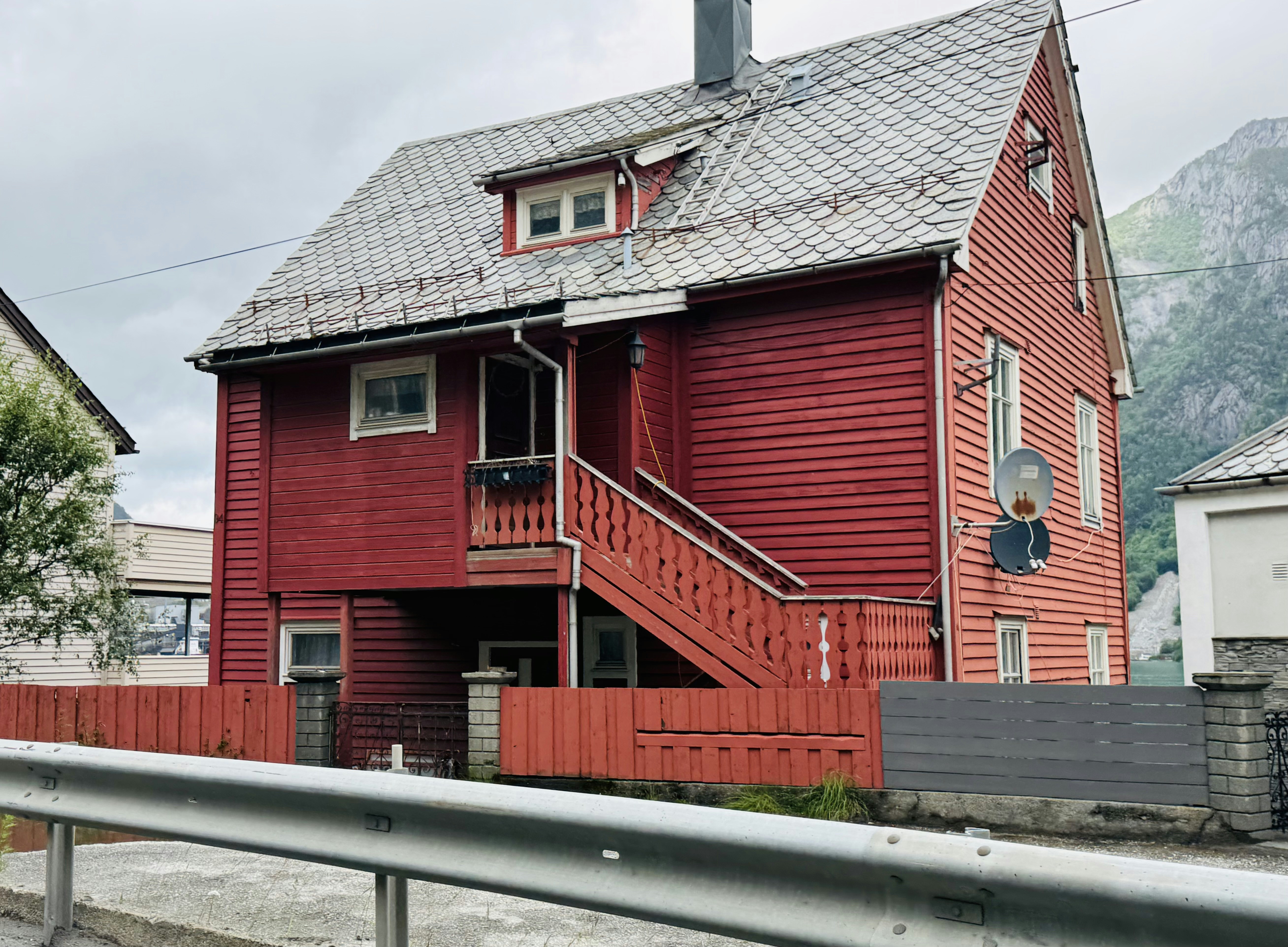 Red House on a Sloping Street Under Mountain Skies