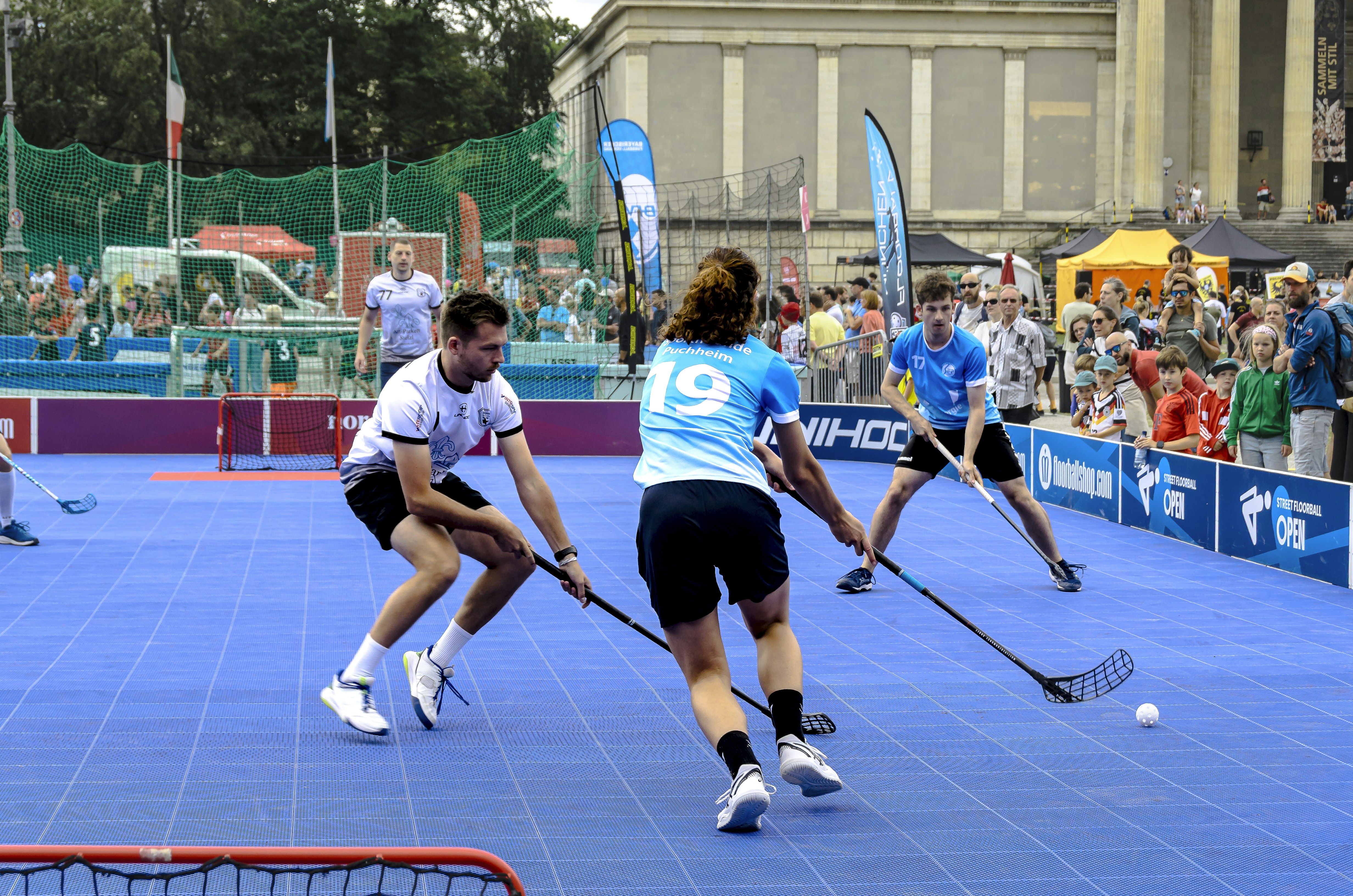Blue-turf Street Hockey Faceoff Under a City Crowd