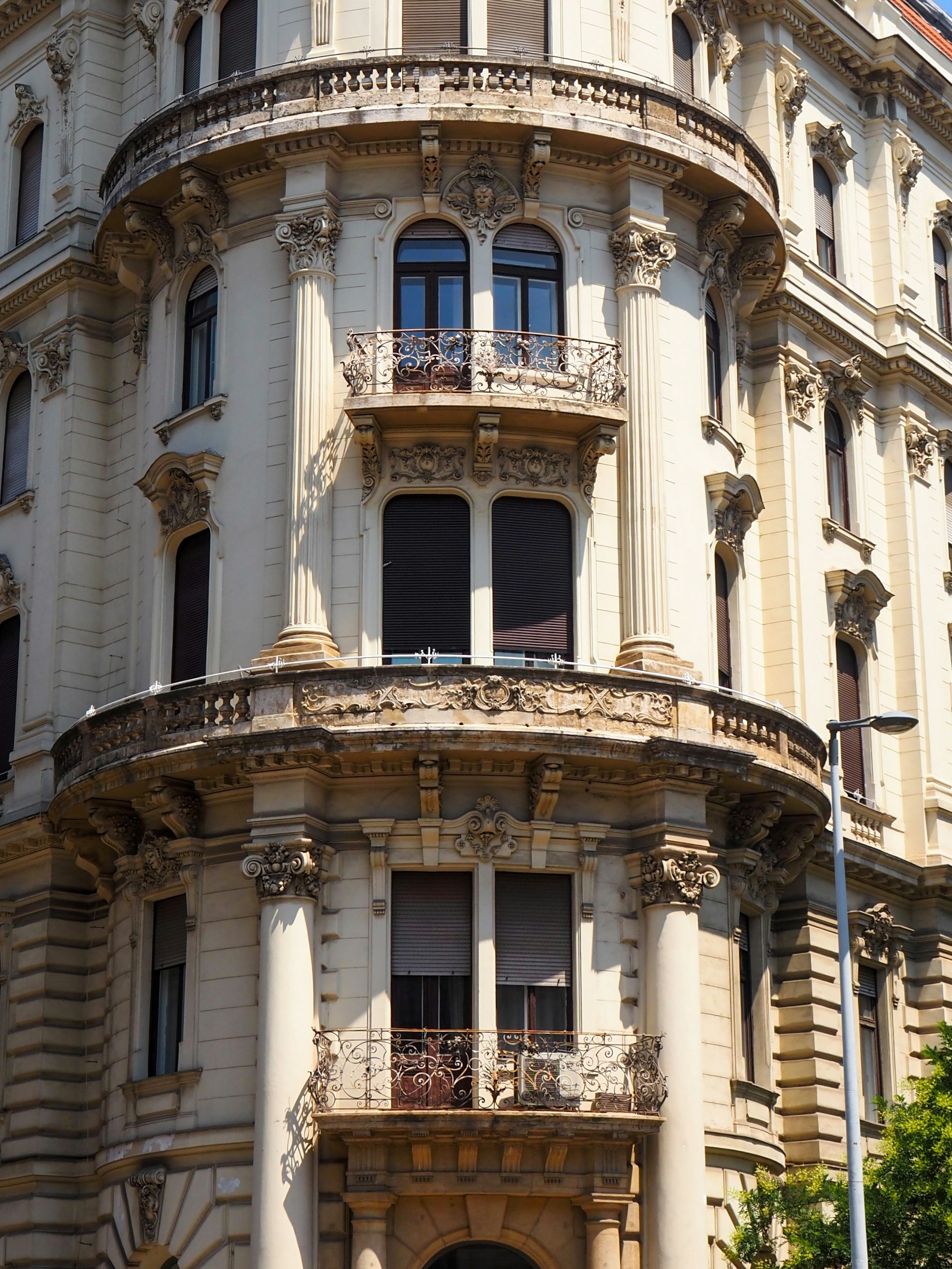 Architectural detail of a grand, light-colored historic facade with ornate balconies and columns, captured in soft daylight.
