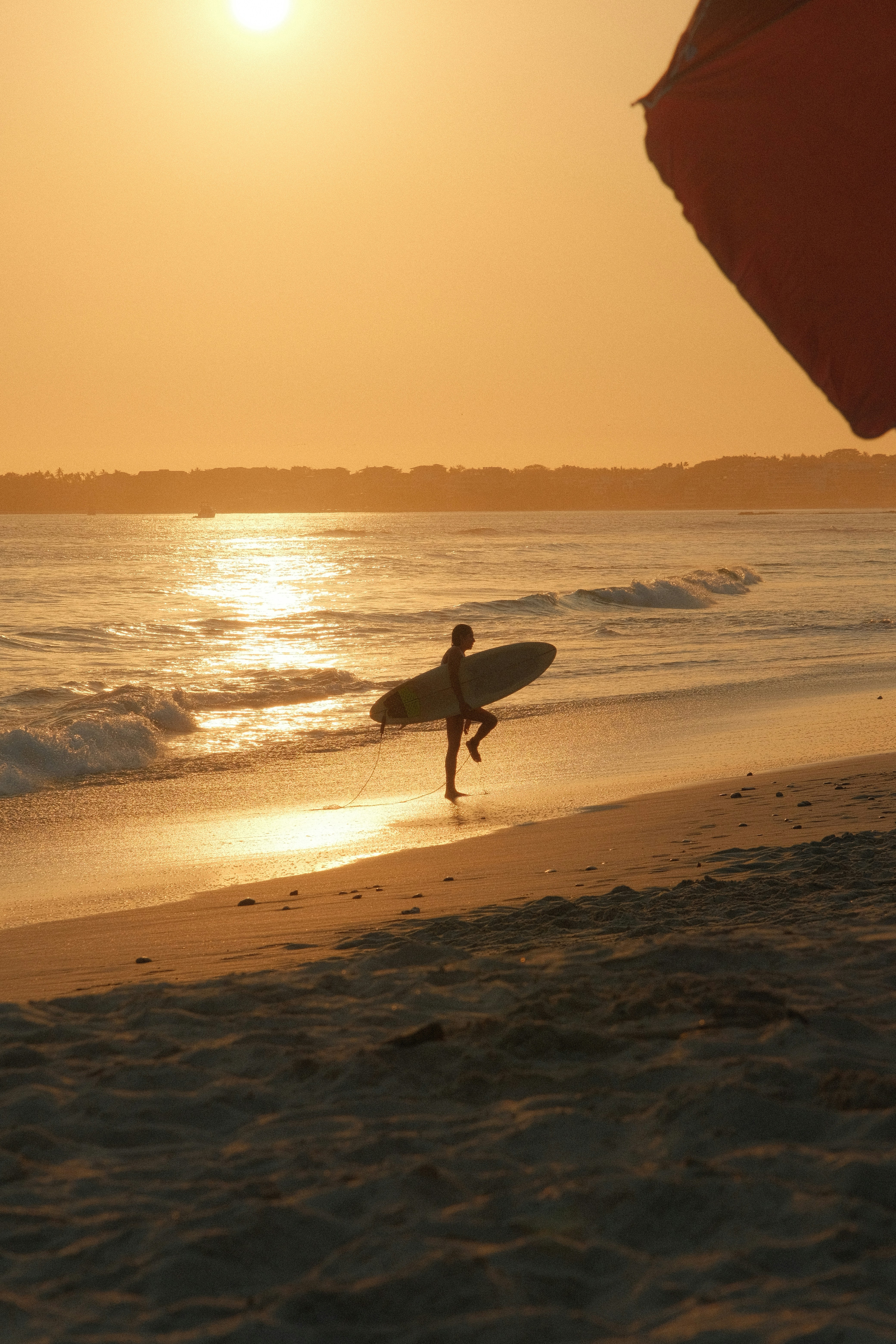 Sunlit shoreline: surfer silhouettes against a golden horizon