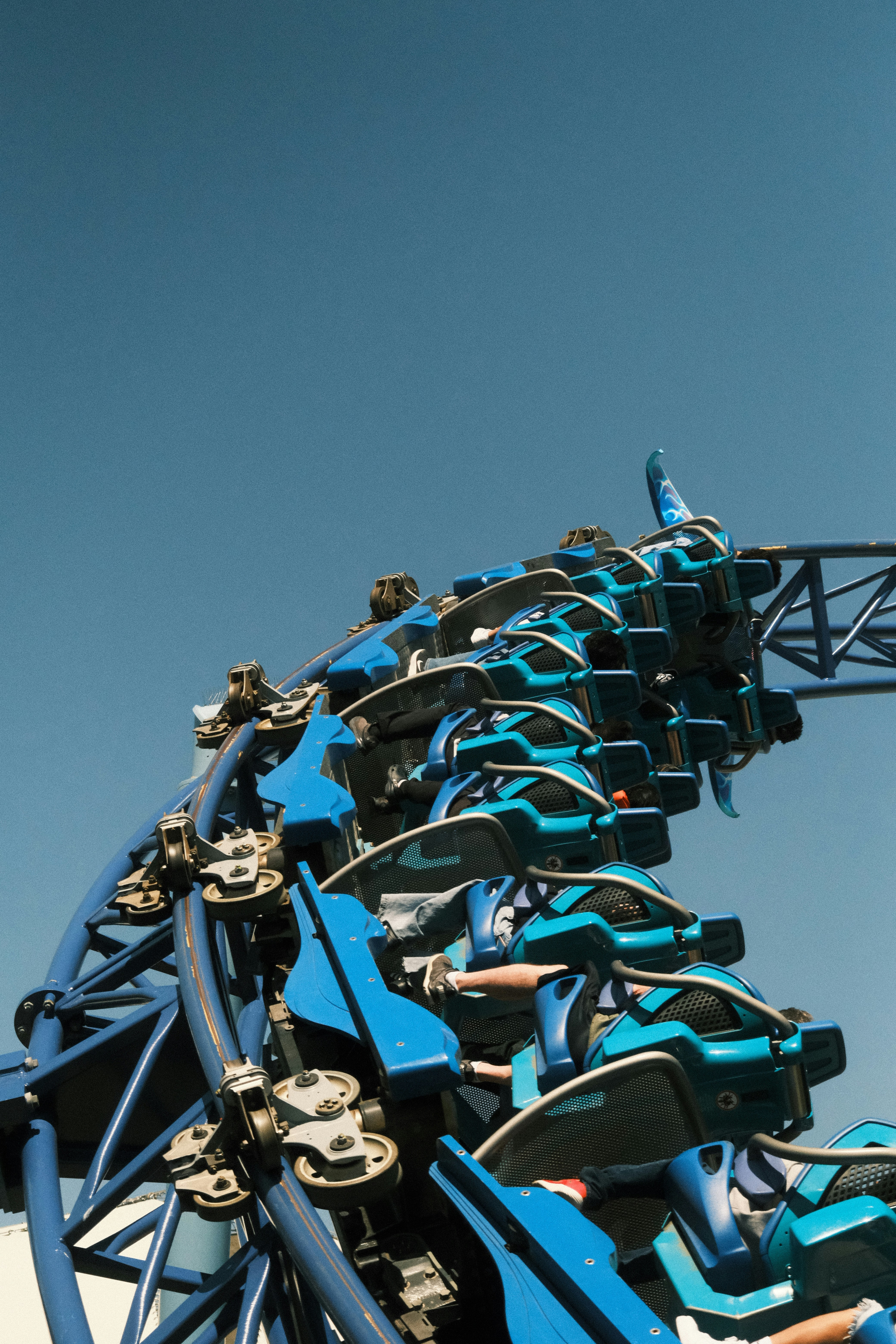 Blue Loop: Riders Halt at the Peak of a Roller Coaster
