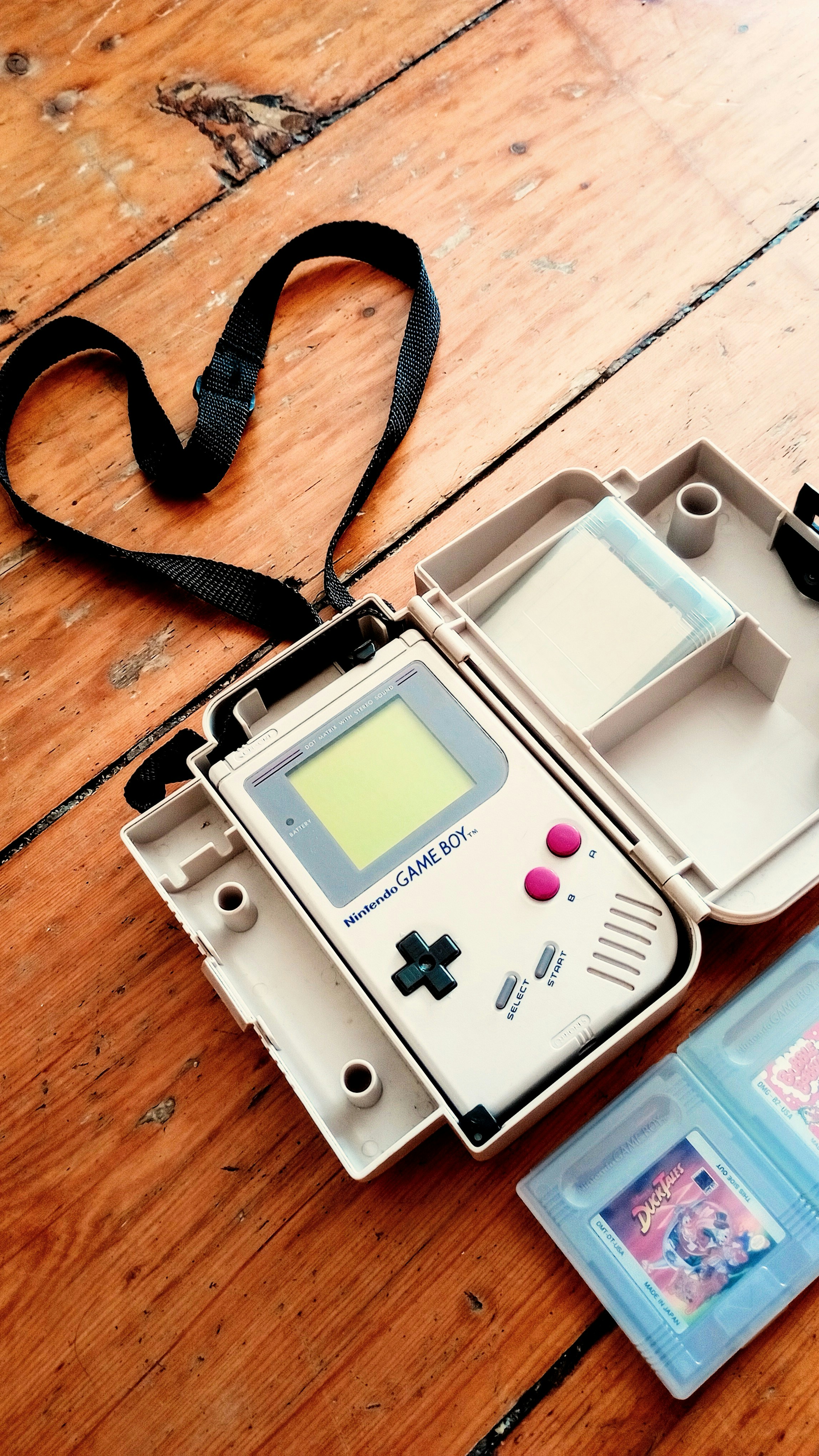 Retro handheld on a wooden stage: an open Game Boy pocket with cartridges nearby