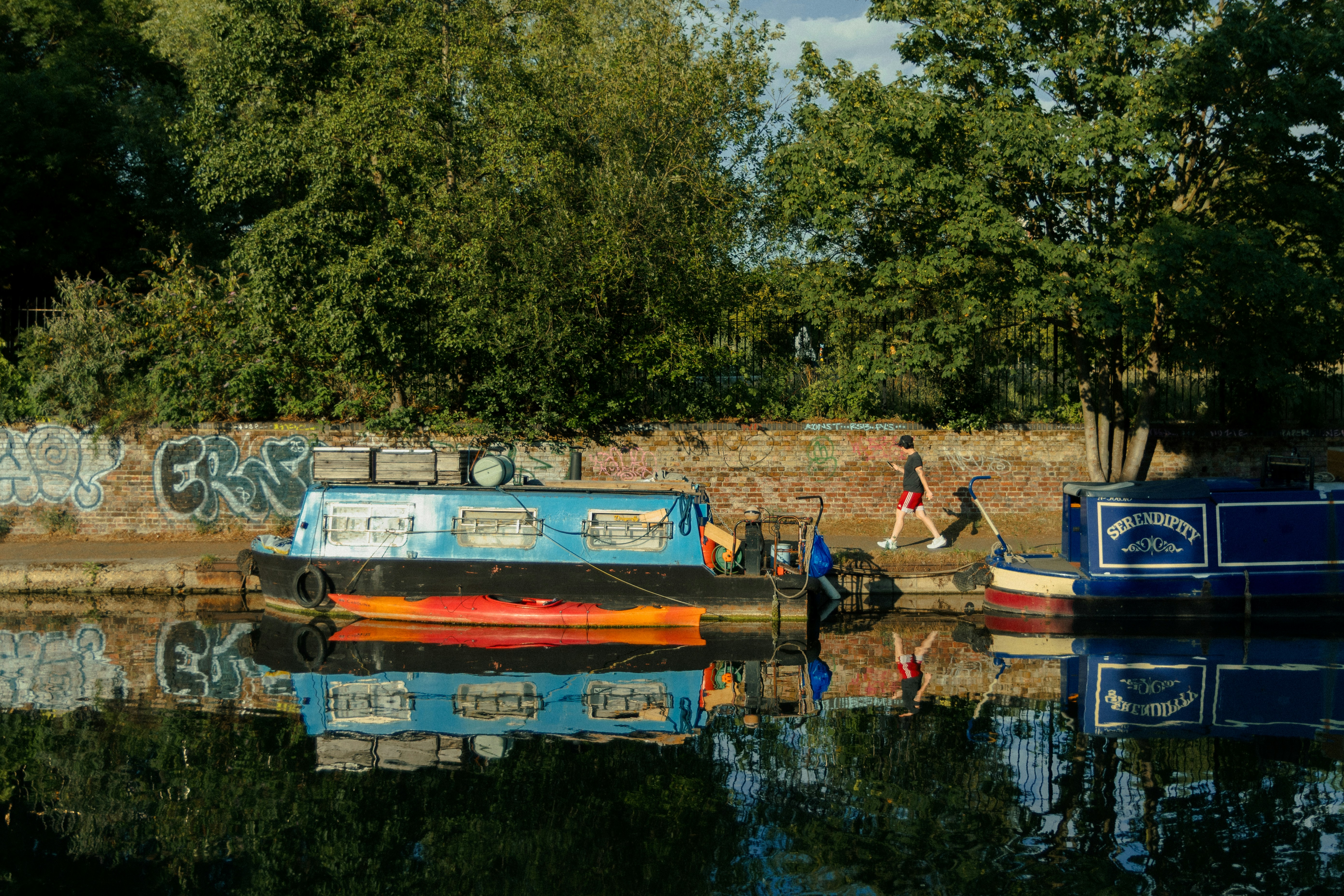 Quiet canal, colorful boats, and a jogger by the riverside