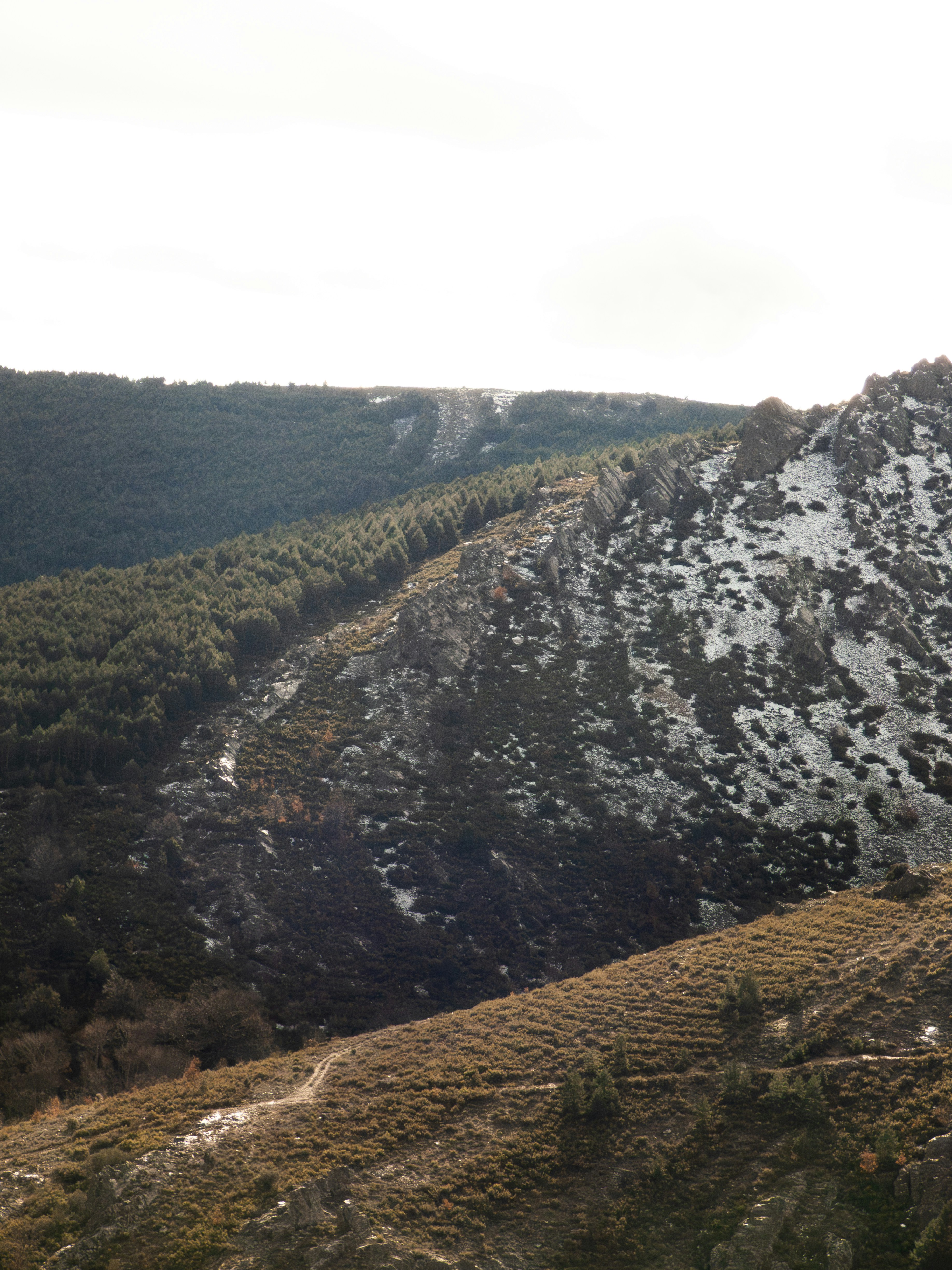 Snow-dusted ridge rolls into a sunlit valley