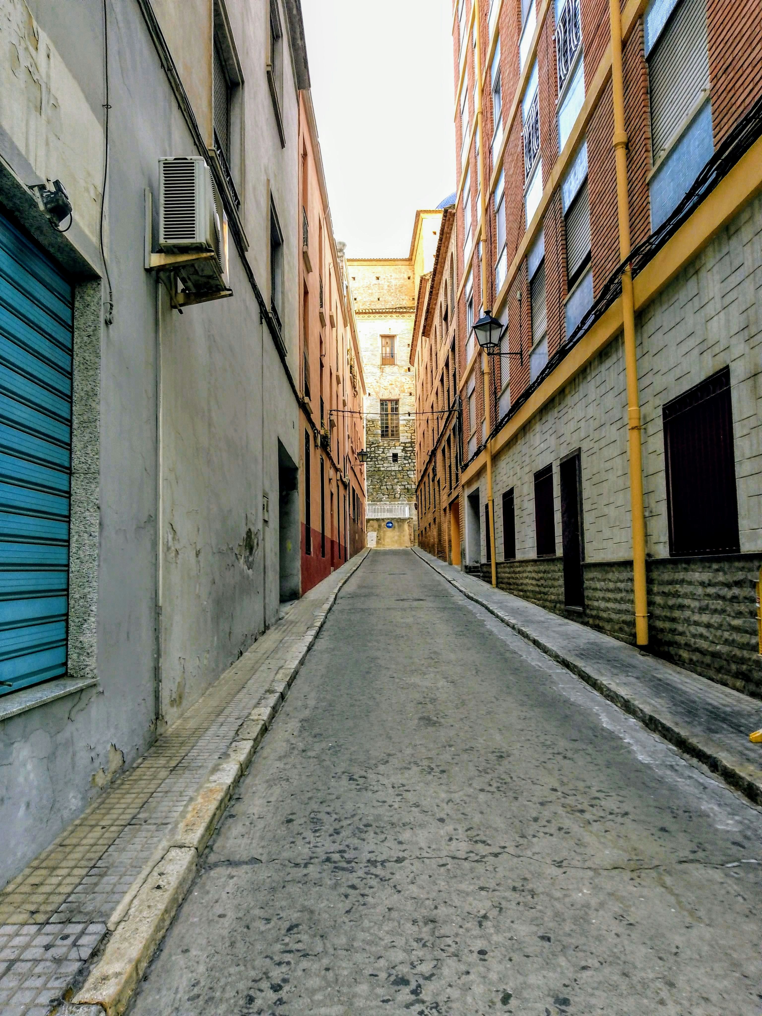 Backstreet in a Spanish town of Oliva, Valencia province. Old concrete, shutters of stores shut, few residents remain here. Cheerful yellow paint creating geometrical patterns in the empty space.