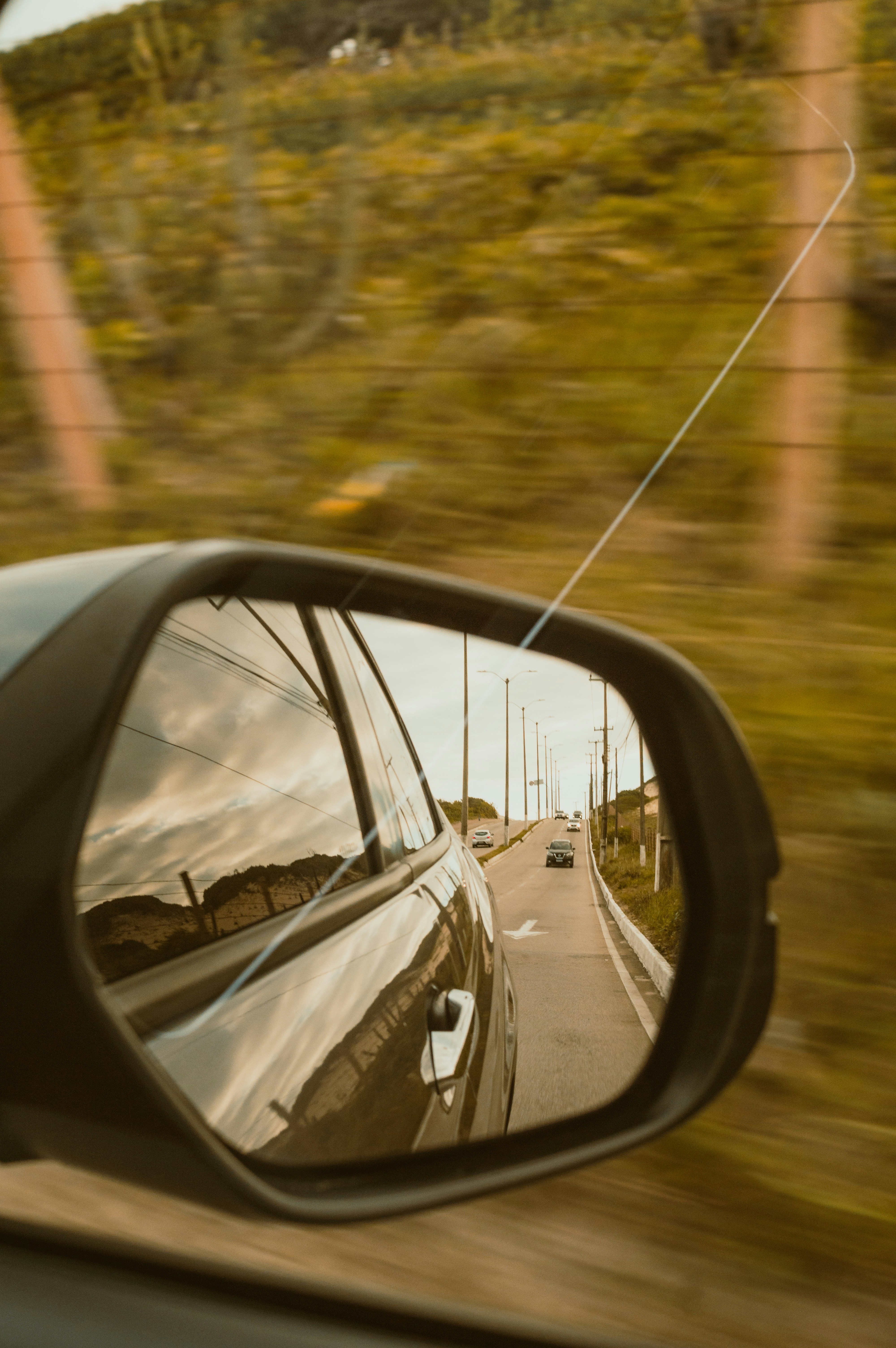 Rear-view Mirror Road: A Blurred Landscape Framing a Moving Moment