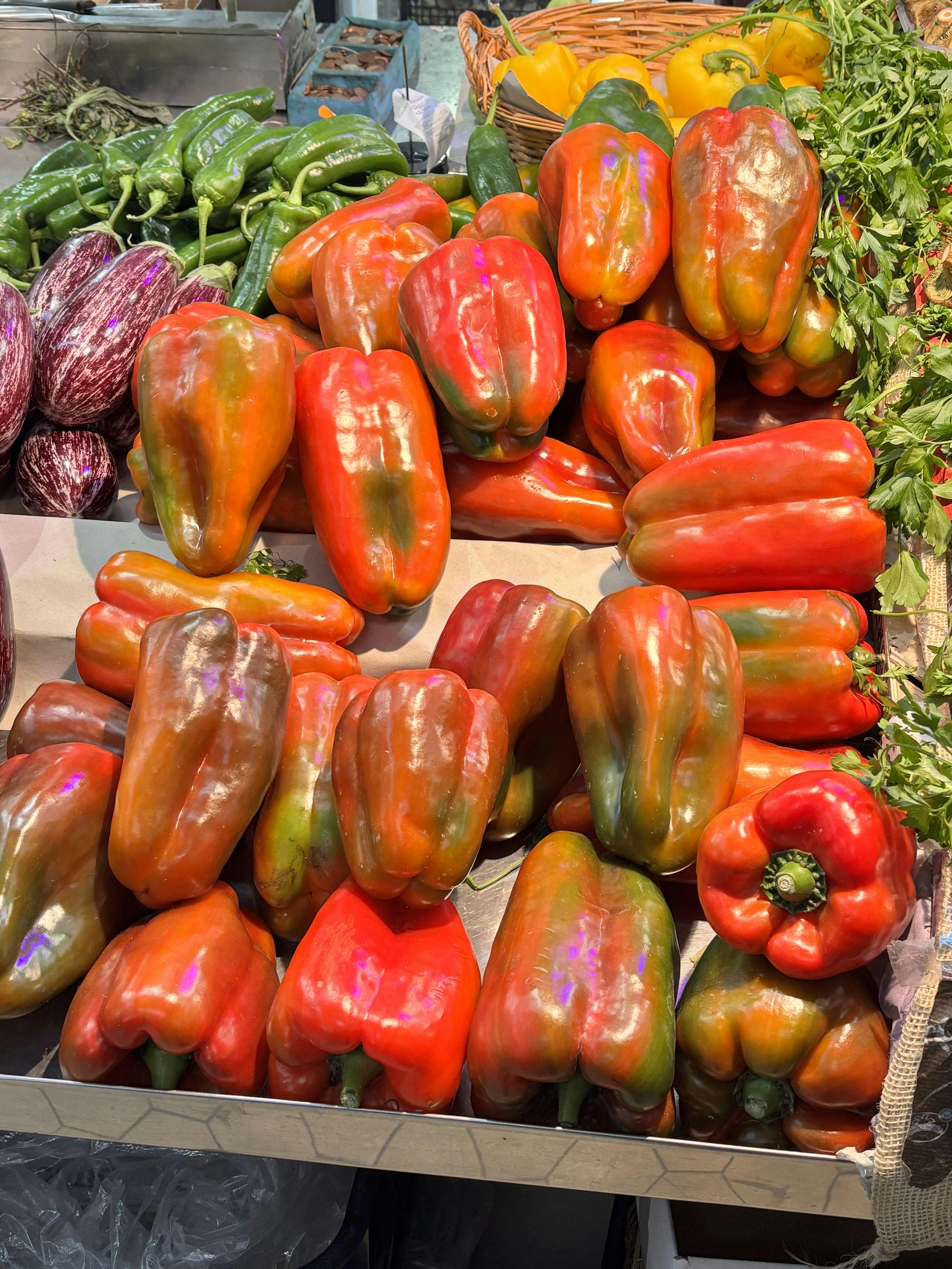 Pile of glossy red bell peppers at a market stall