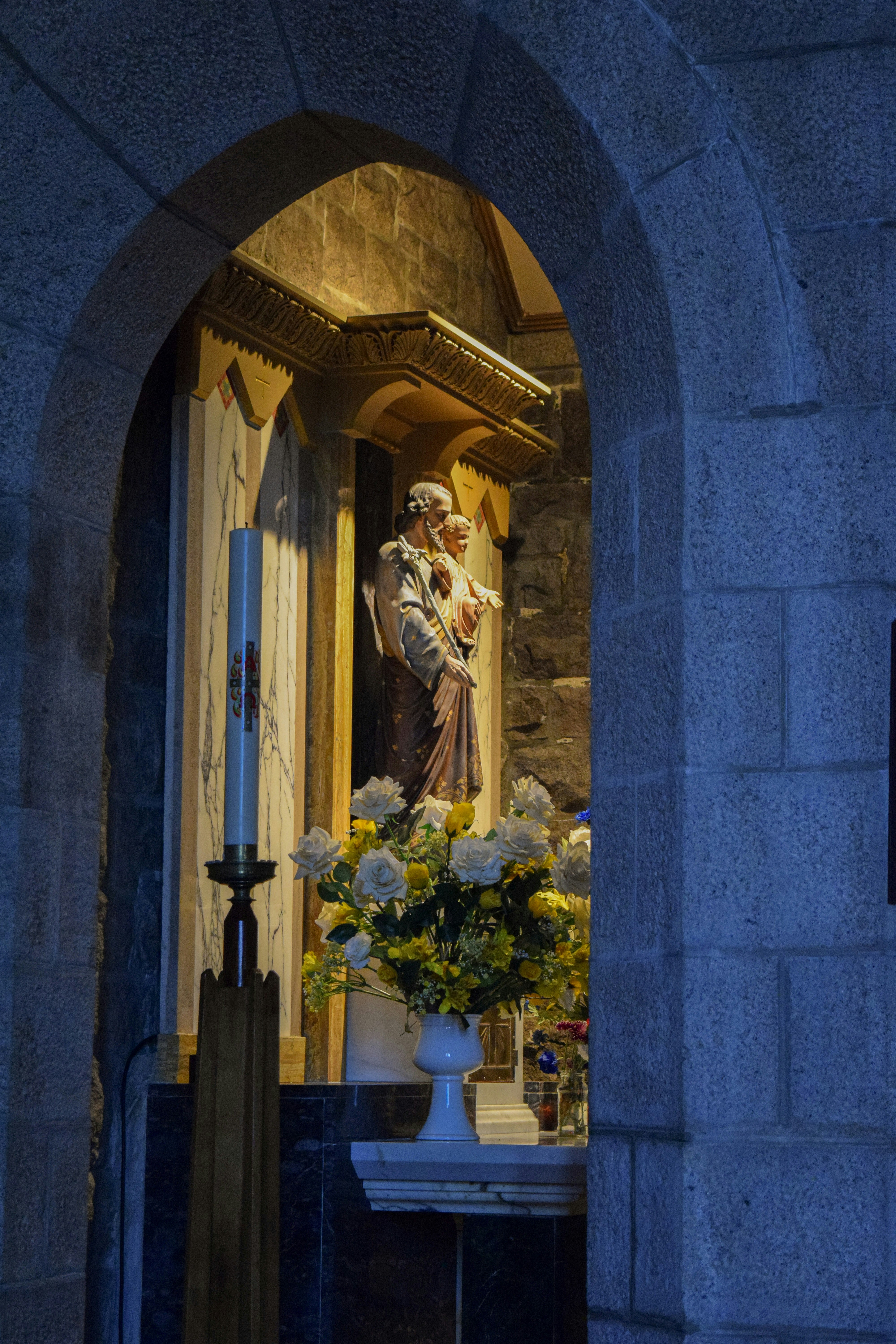 Quiet Shrine: Statue Amidst Stone Archway Bathed in Warm Light