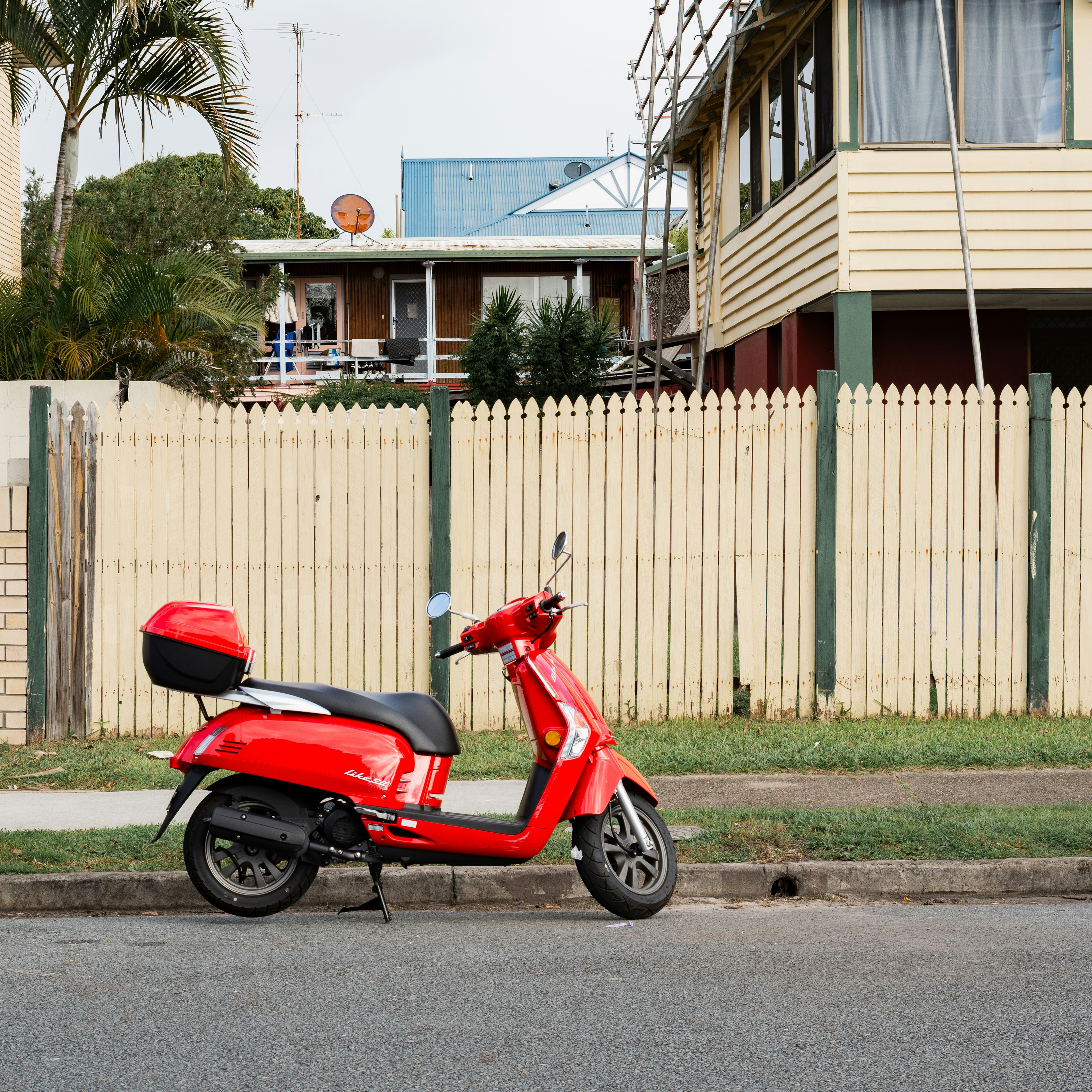 Red Scooter at the Edge of Suburban Street