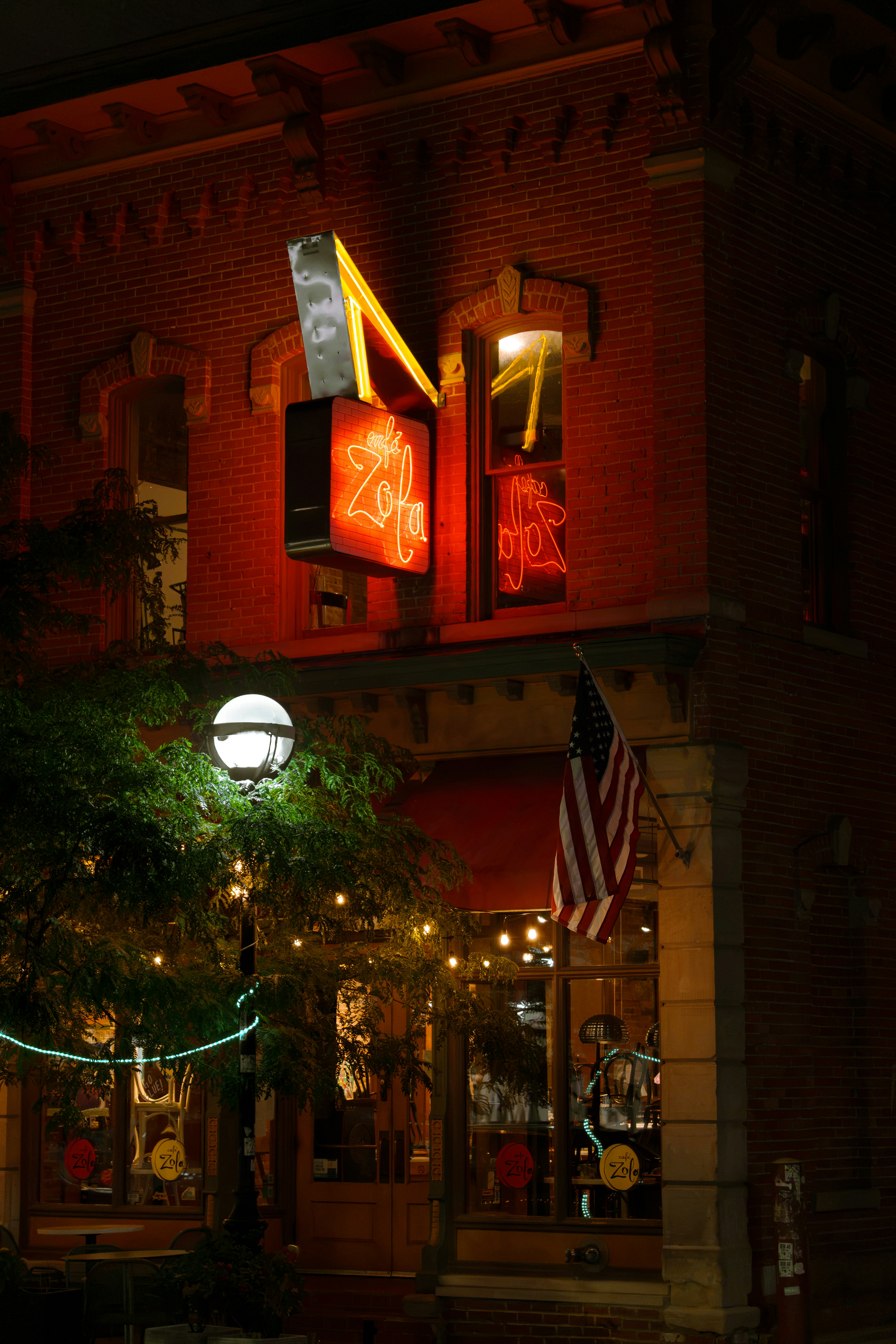Neon Signage and American Flag Quietly Framing a Brick Corner