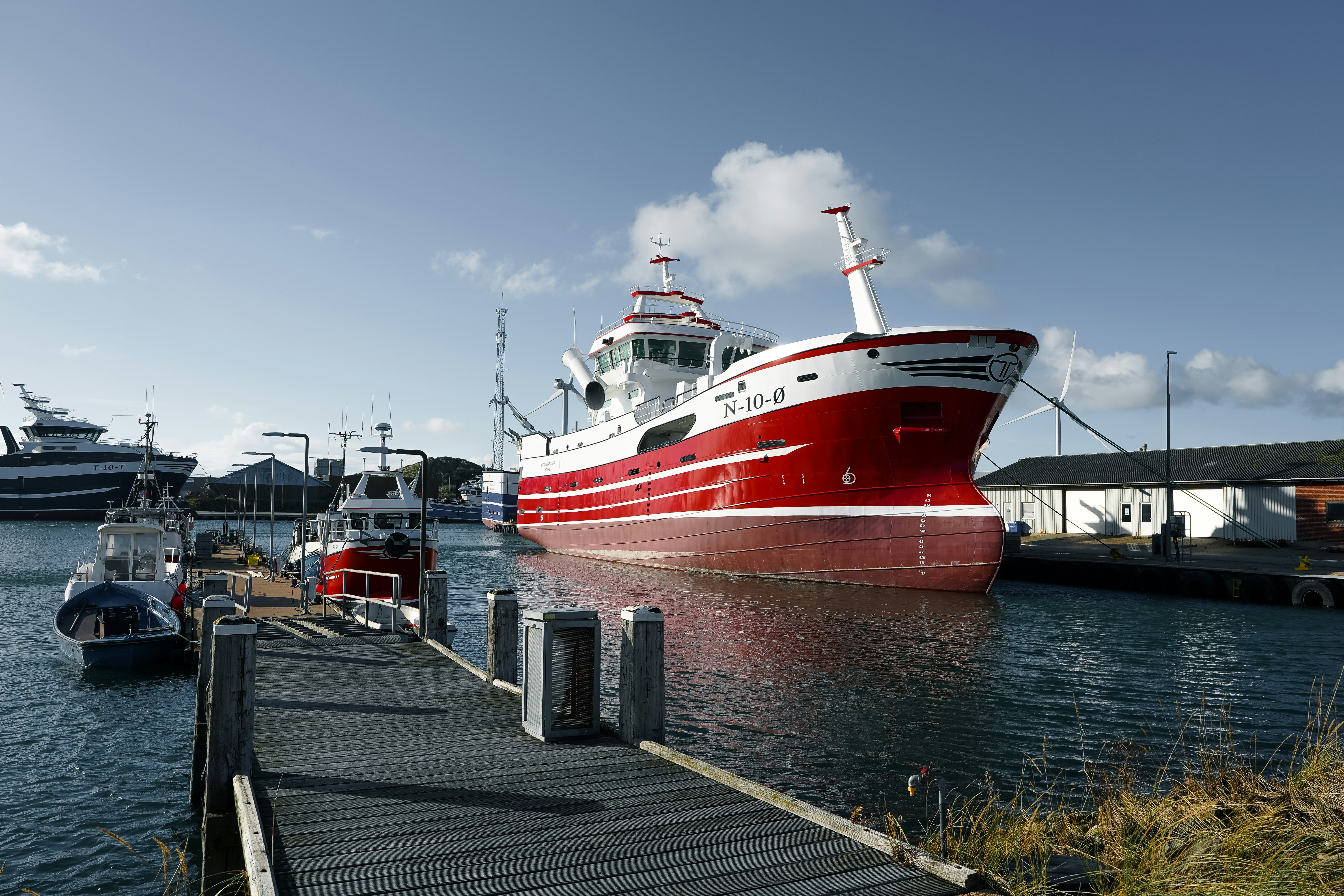 Red Twin-hull of the Sea Queen moored beside a sleepy wooden pier