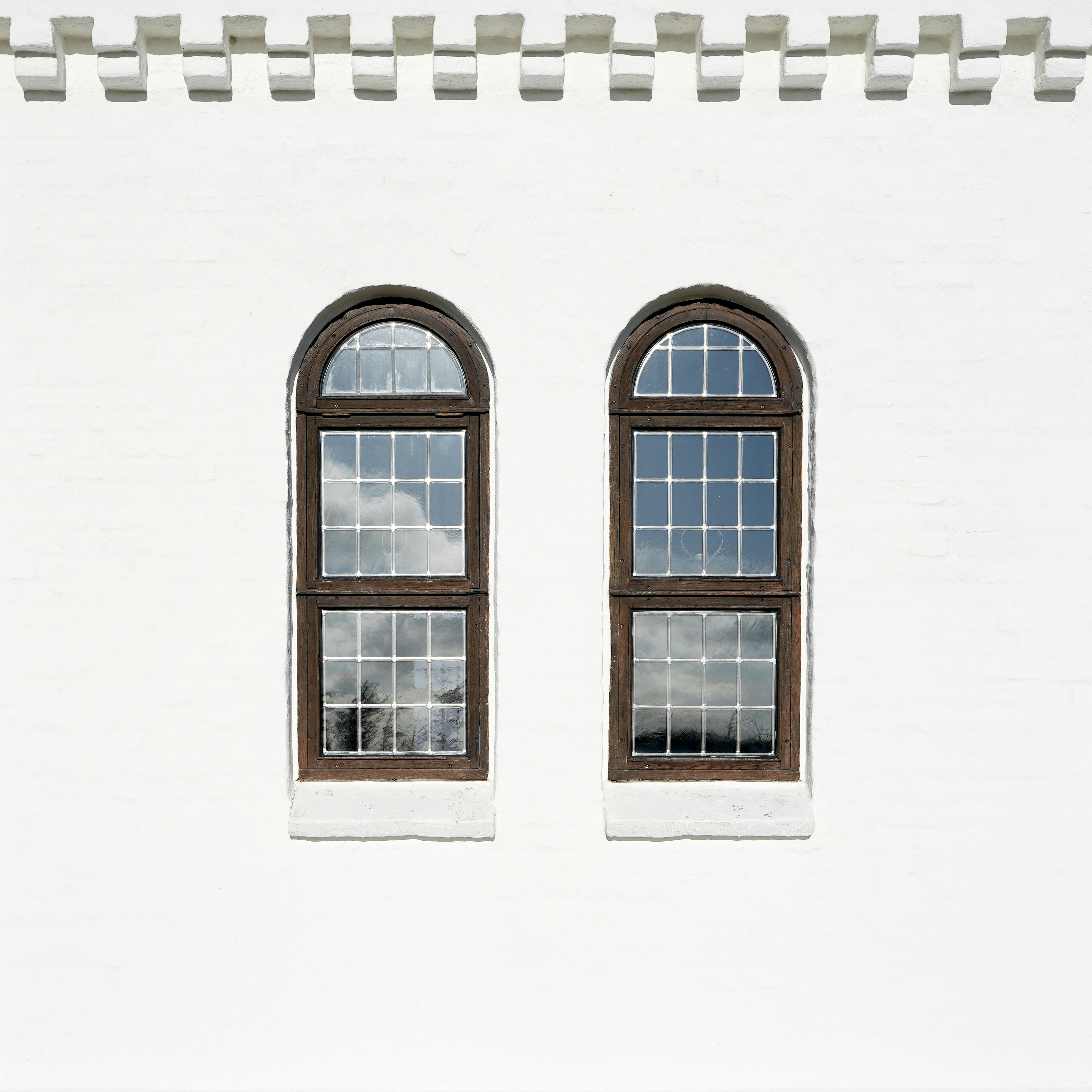 Twin Arched Windows in a Sunlit White Facade